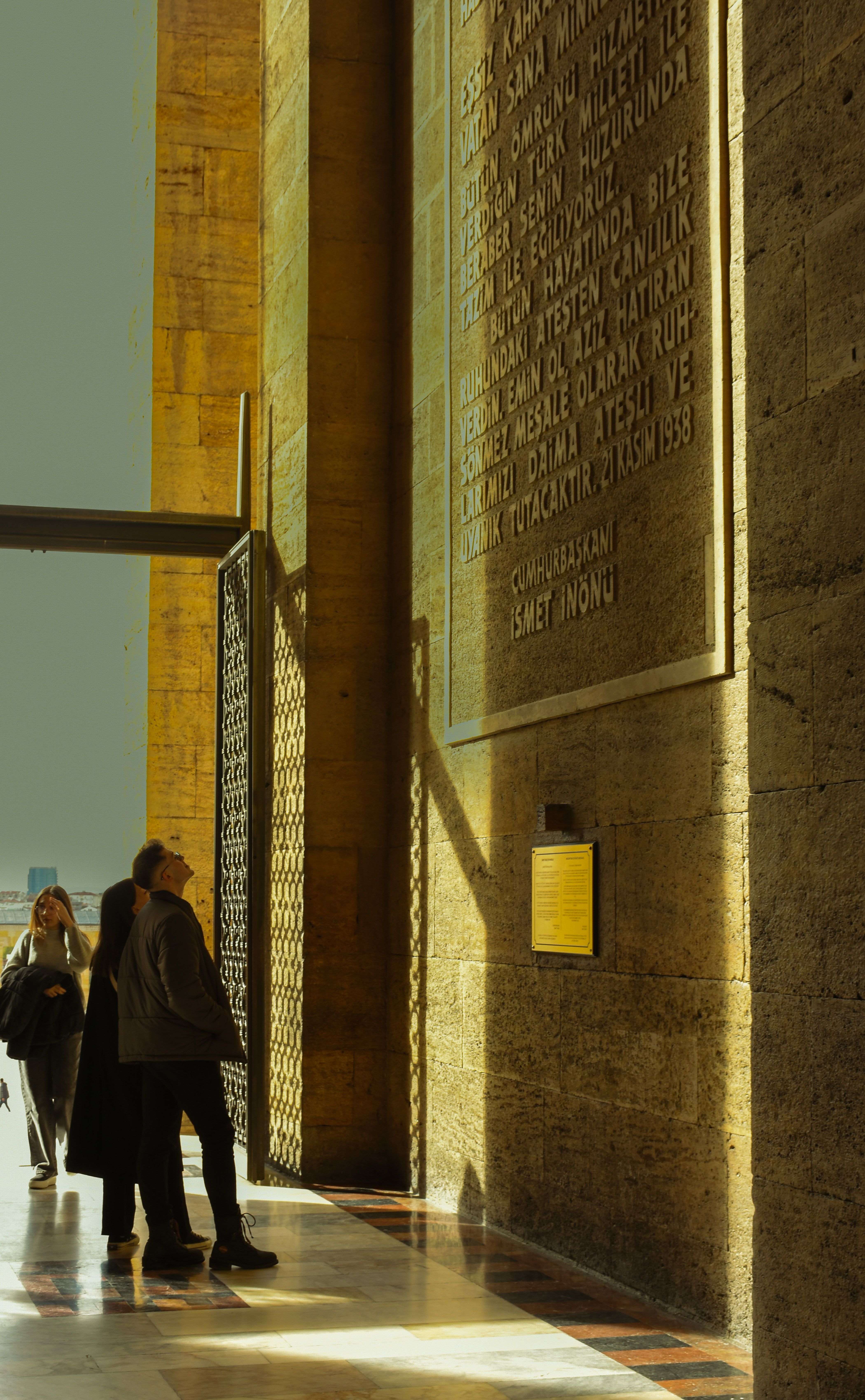 Two people walking through a building with a large wall · Free Stock Photo