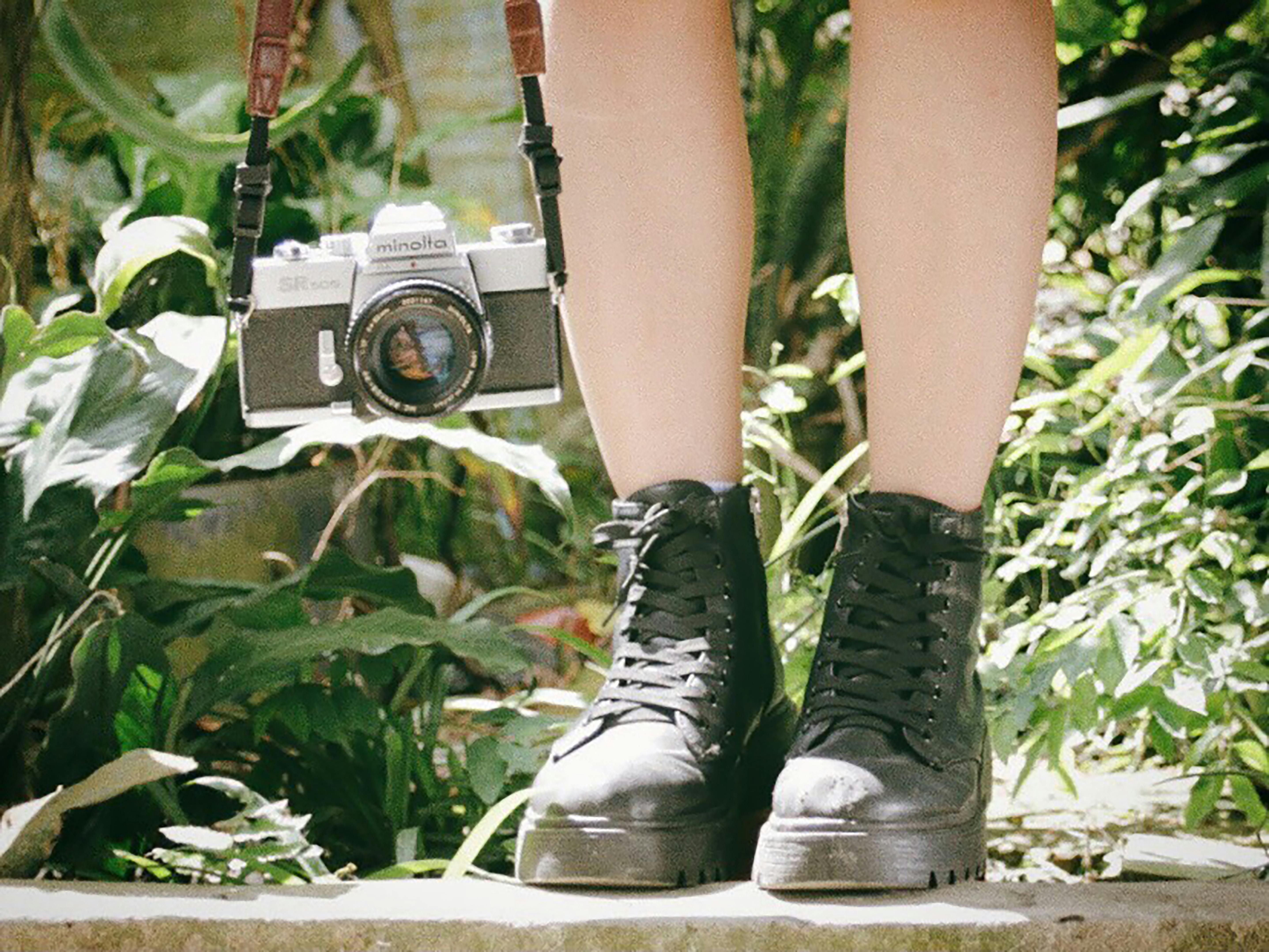 A person wearing black boots and a camera · Free Stock Photo