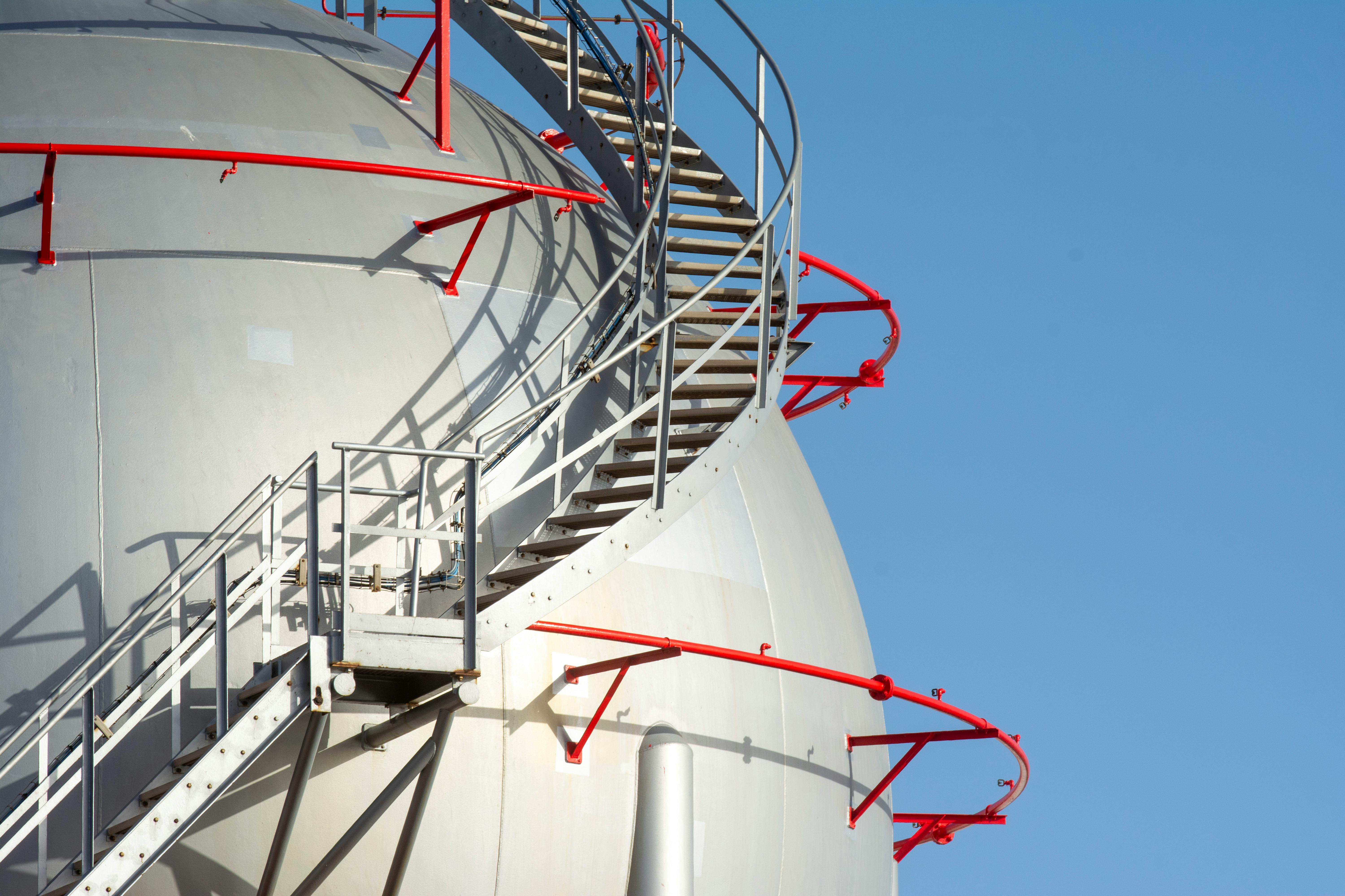 A large industrial tank with stairs and a red railing · Free Stock Photo