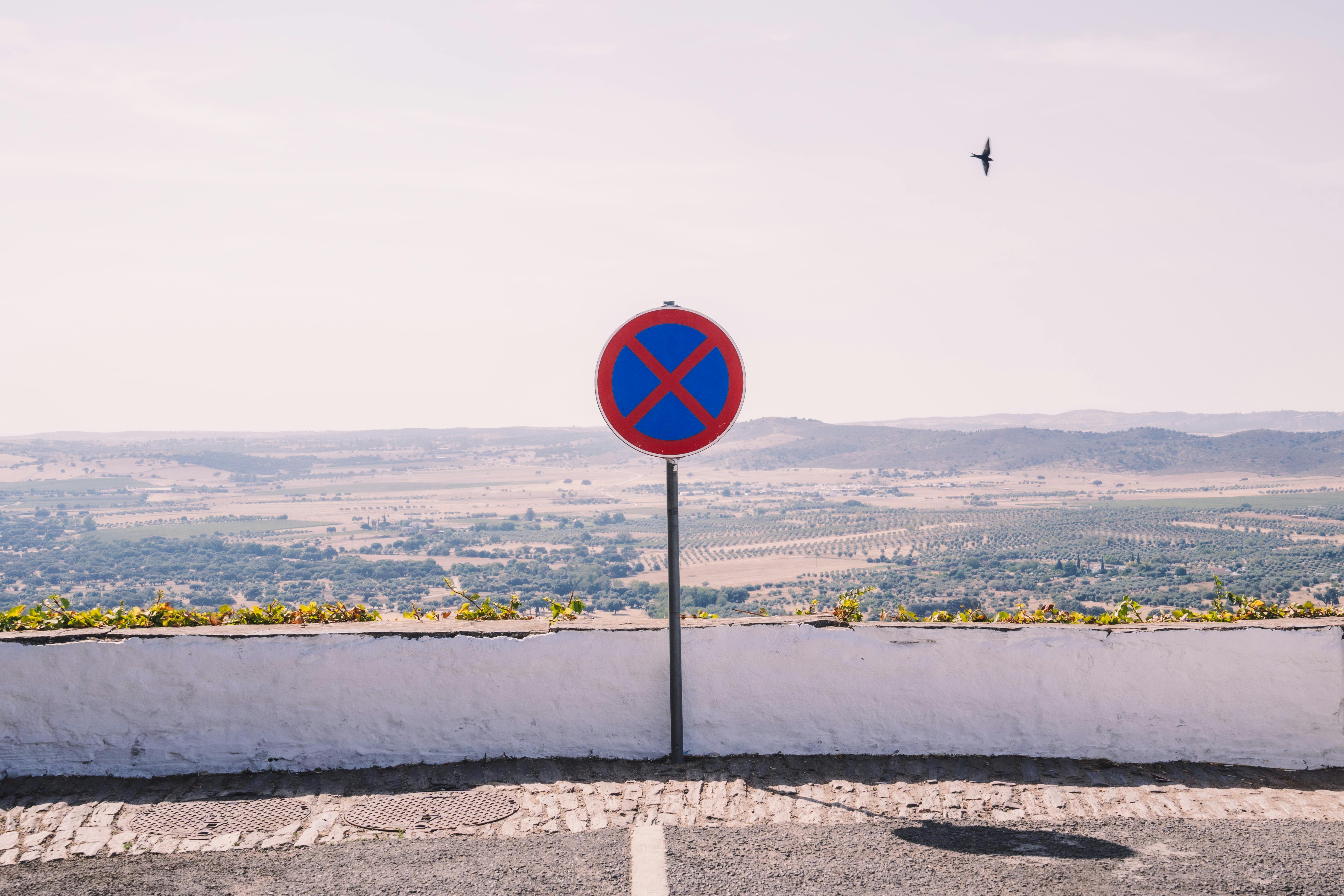 A blue and red stop sign on a white wall · Free Stock Photo