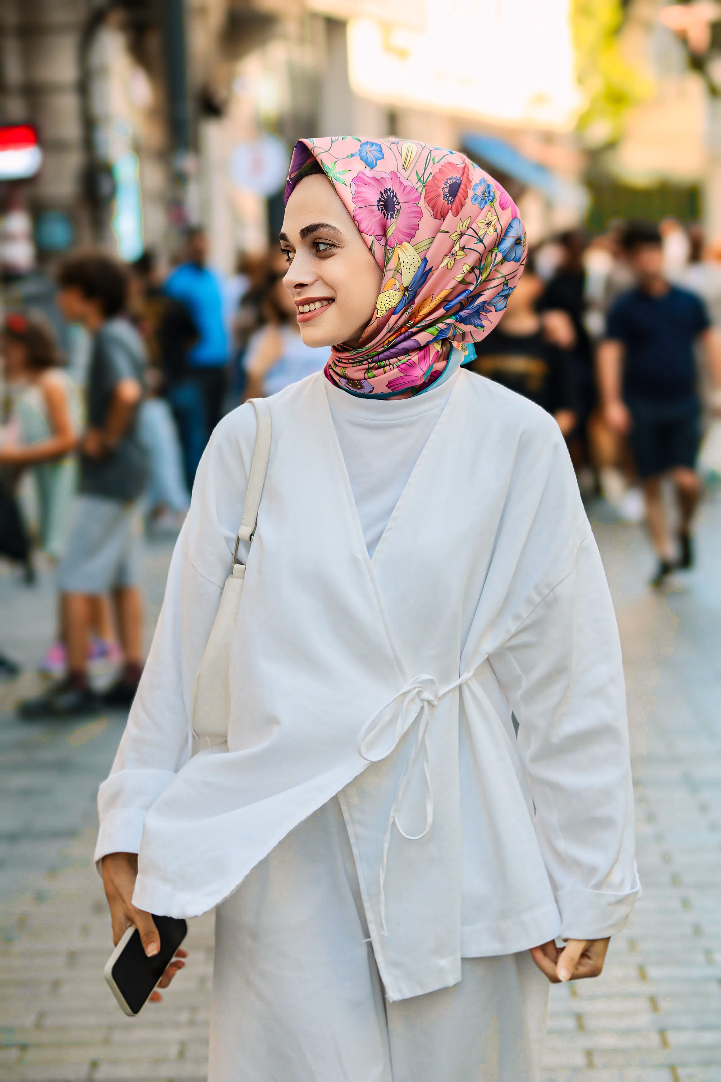 A woman in a white outfit and headscarf walking down a street · Free ...