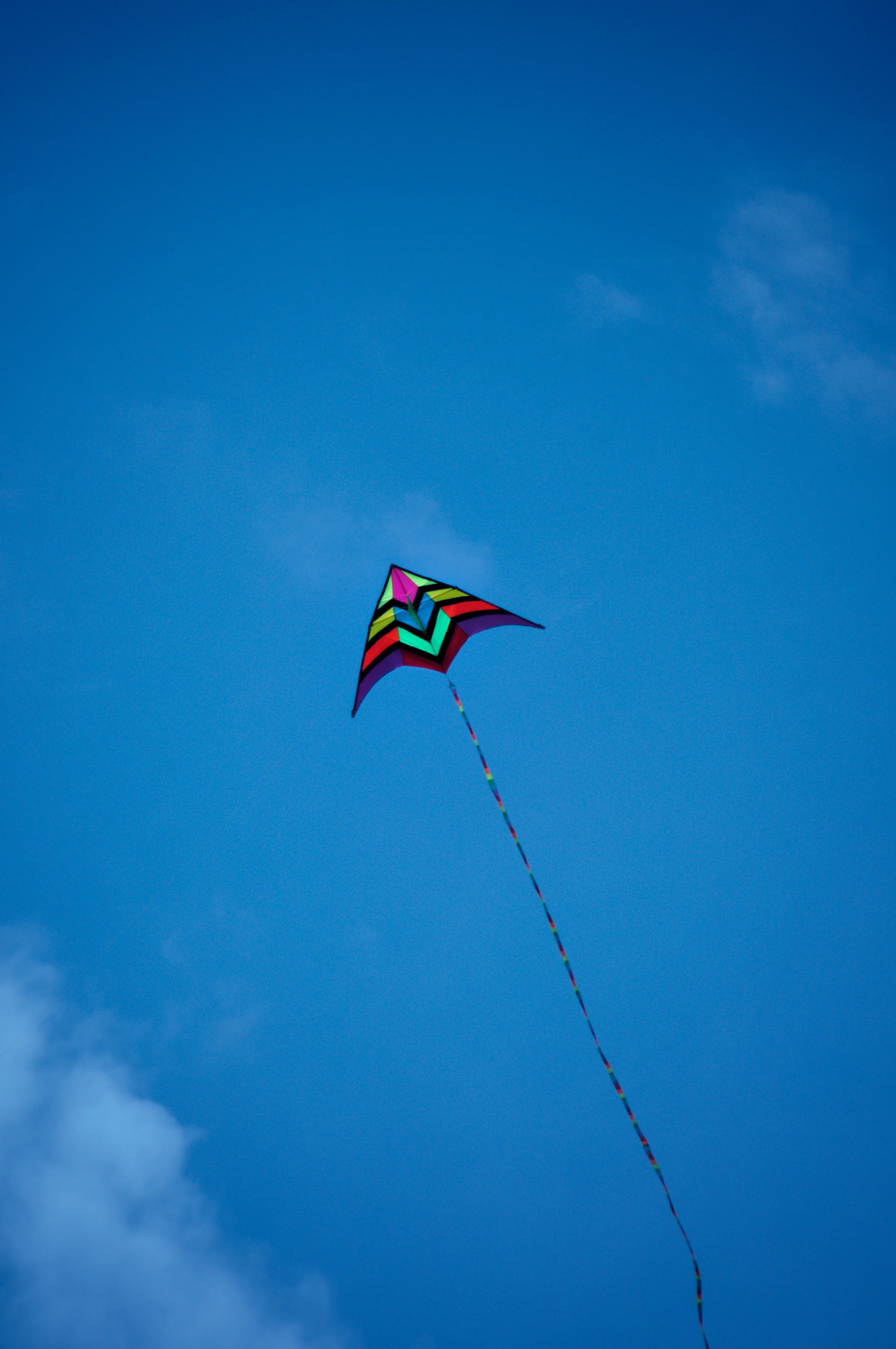 A kite flying in the sky with a colorful tail · Free Stock Photo