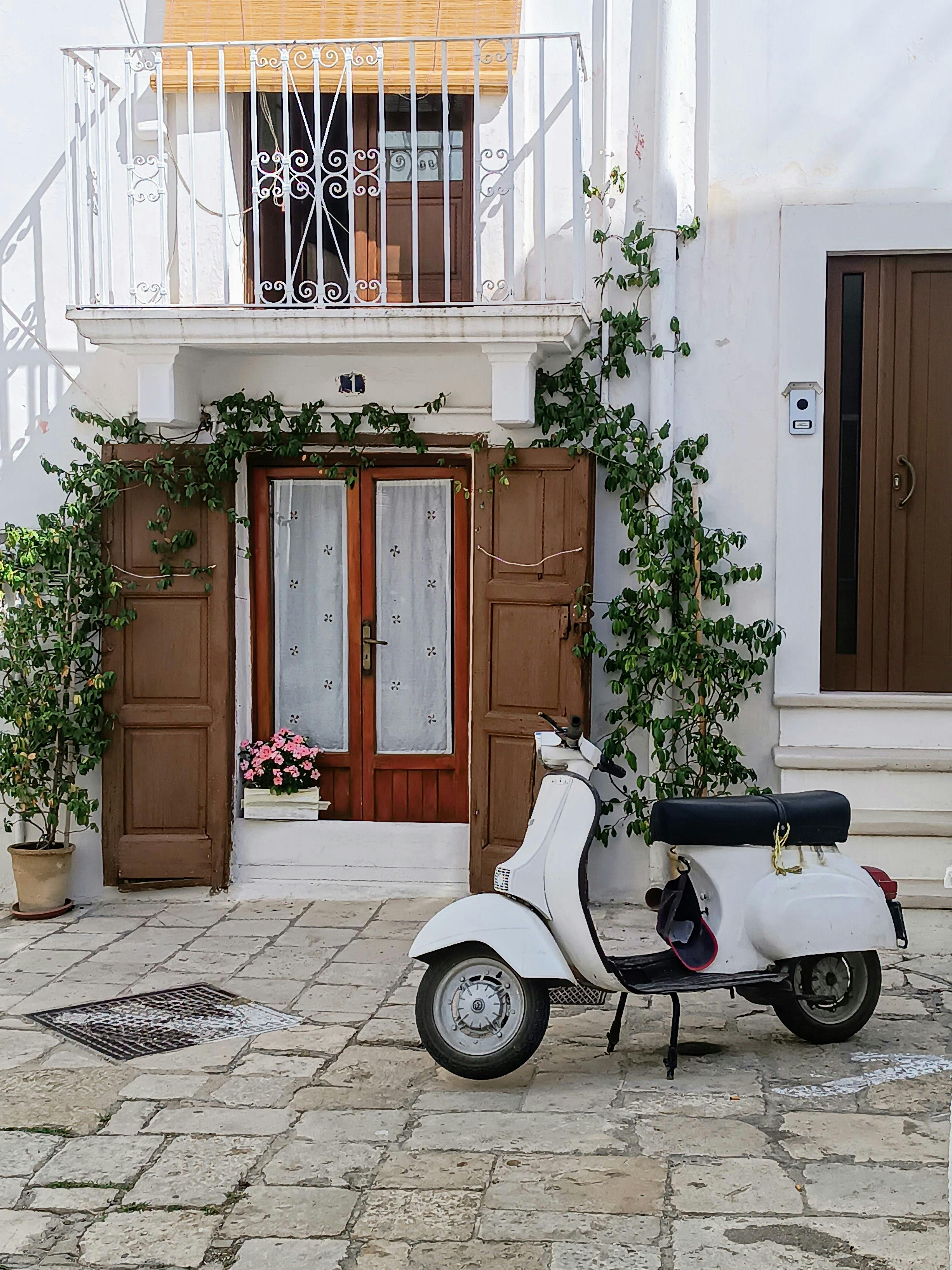 A white moped parked in front of a house · Free Stock Photo