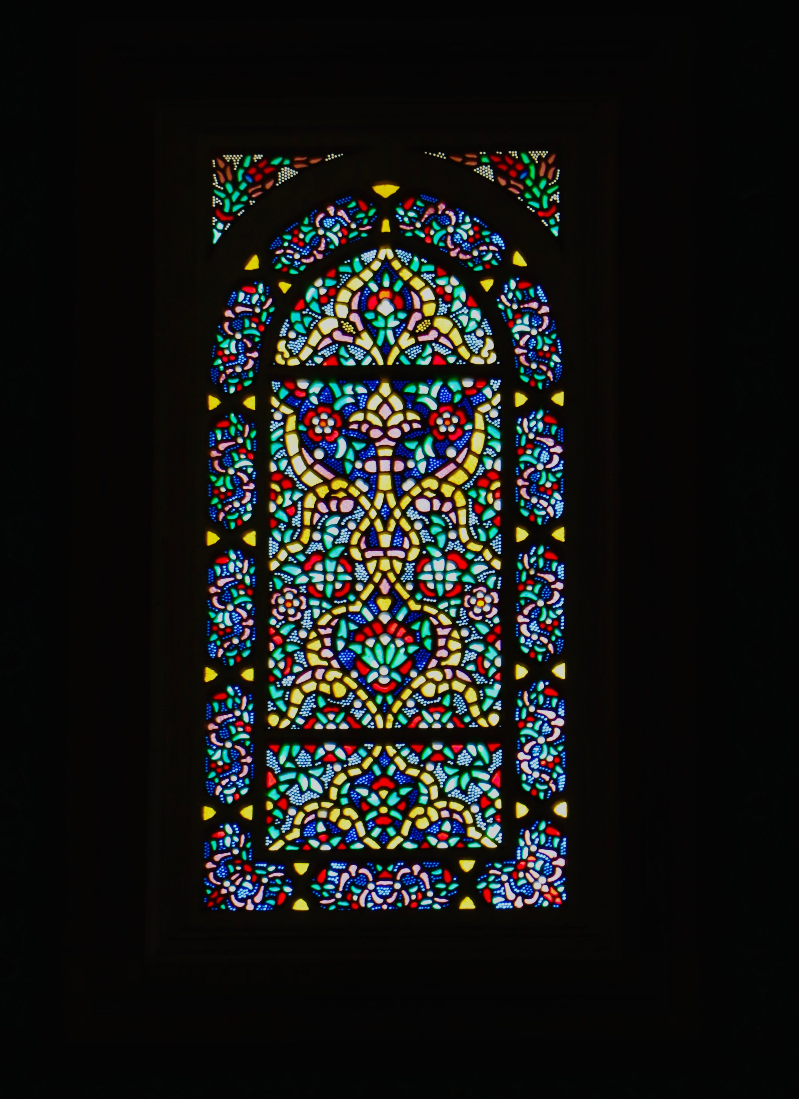 A stained glass window in a dark room · Free Stock Photo