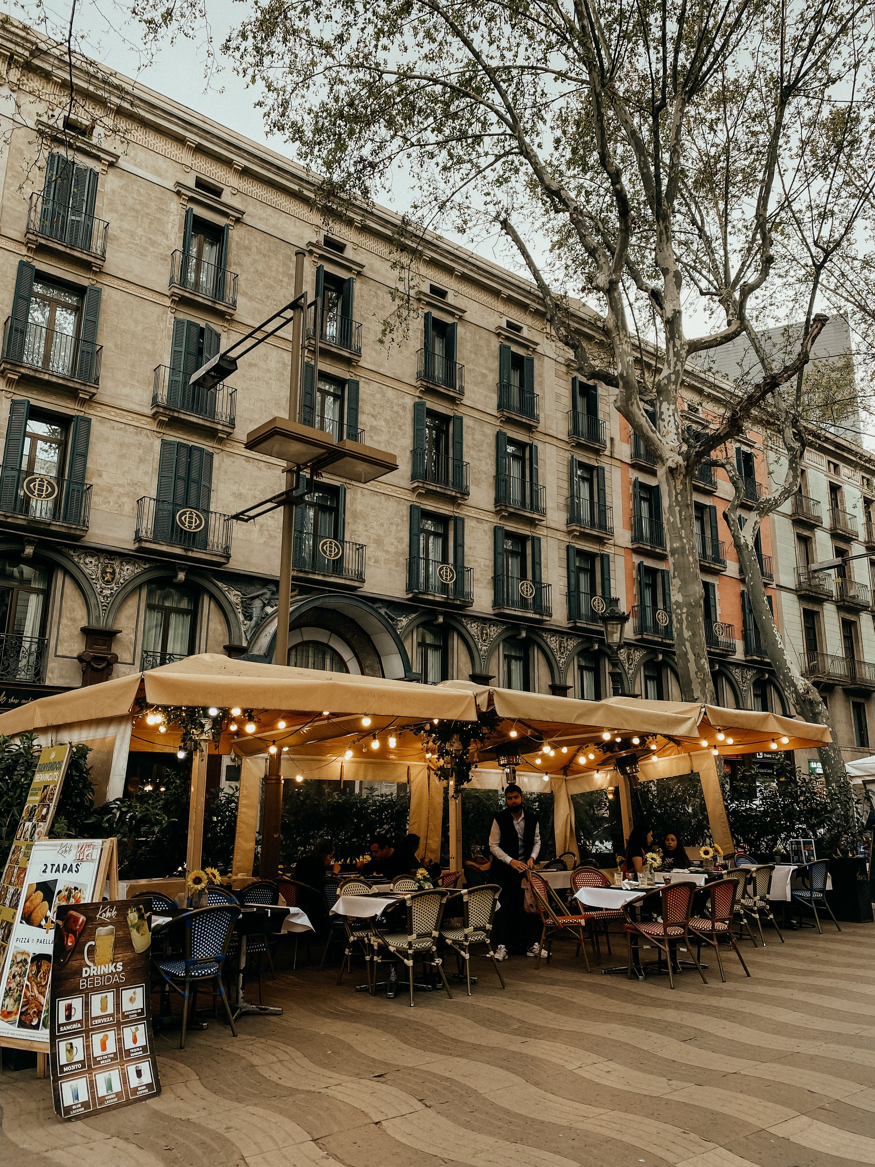 A cafe with tables and chairs in front of a building · Free Stock Photo