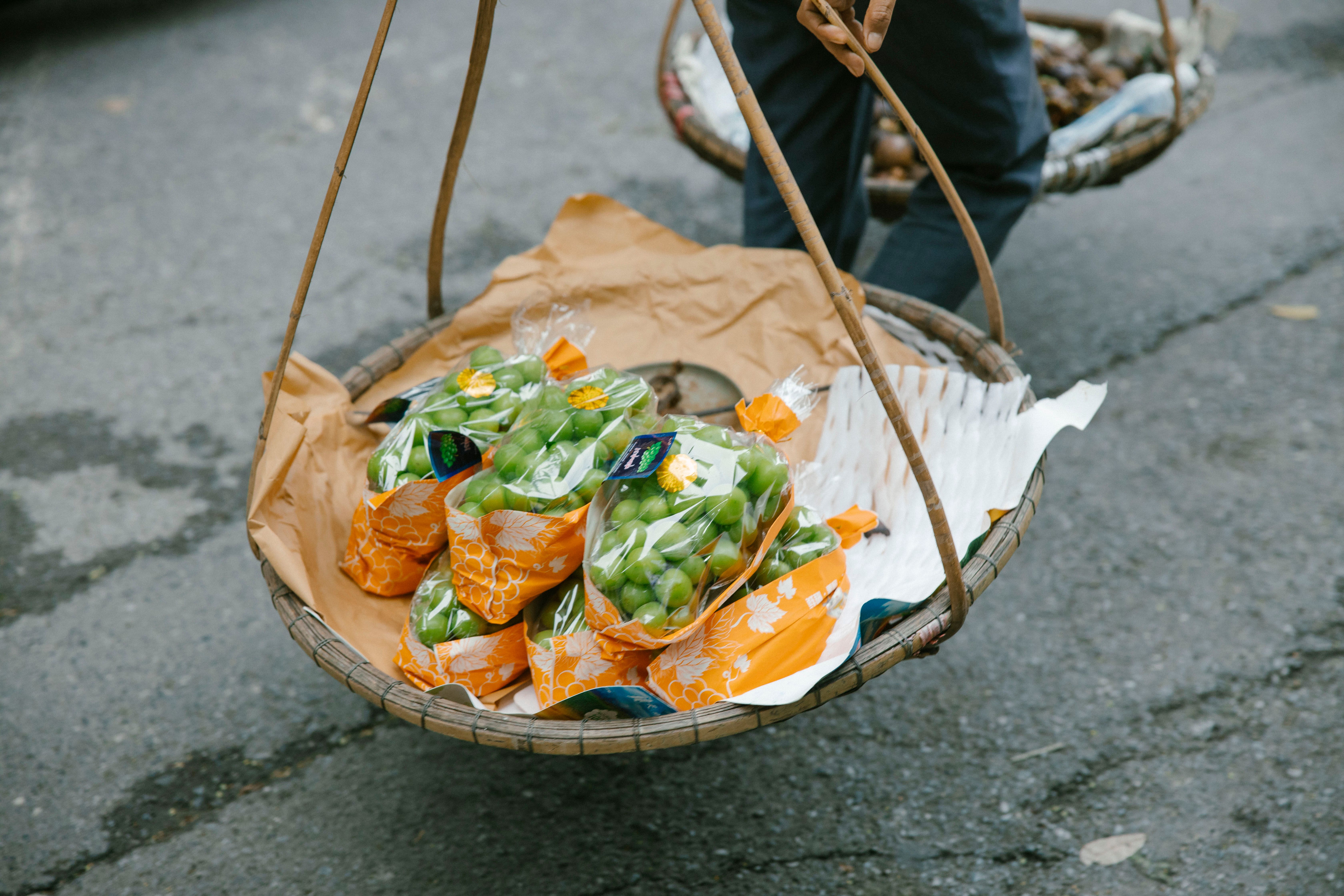 A person carrying a basket of food on a street · Free Stock Photo