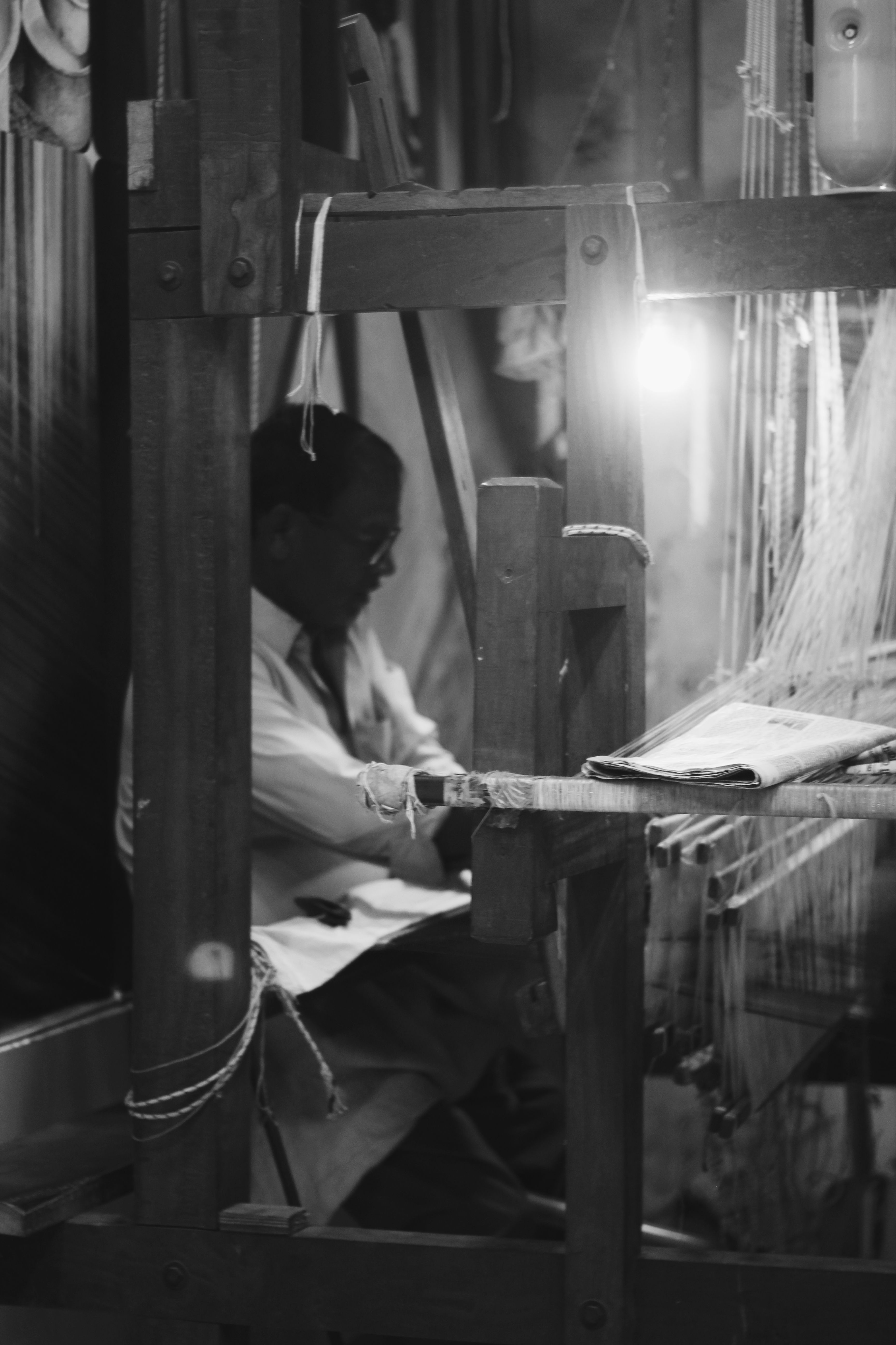 A man working on a loom in a dark room · Free Stock Photo