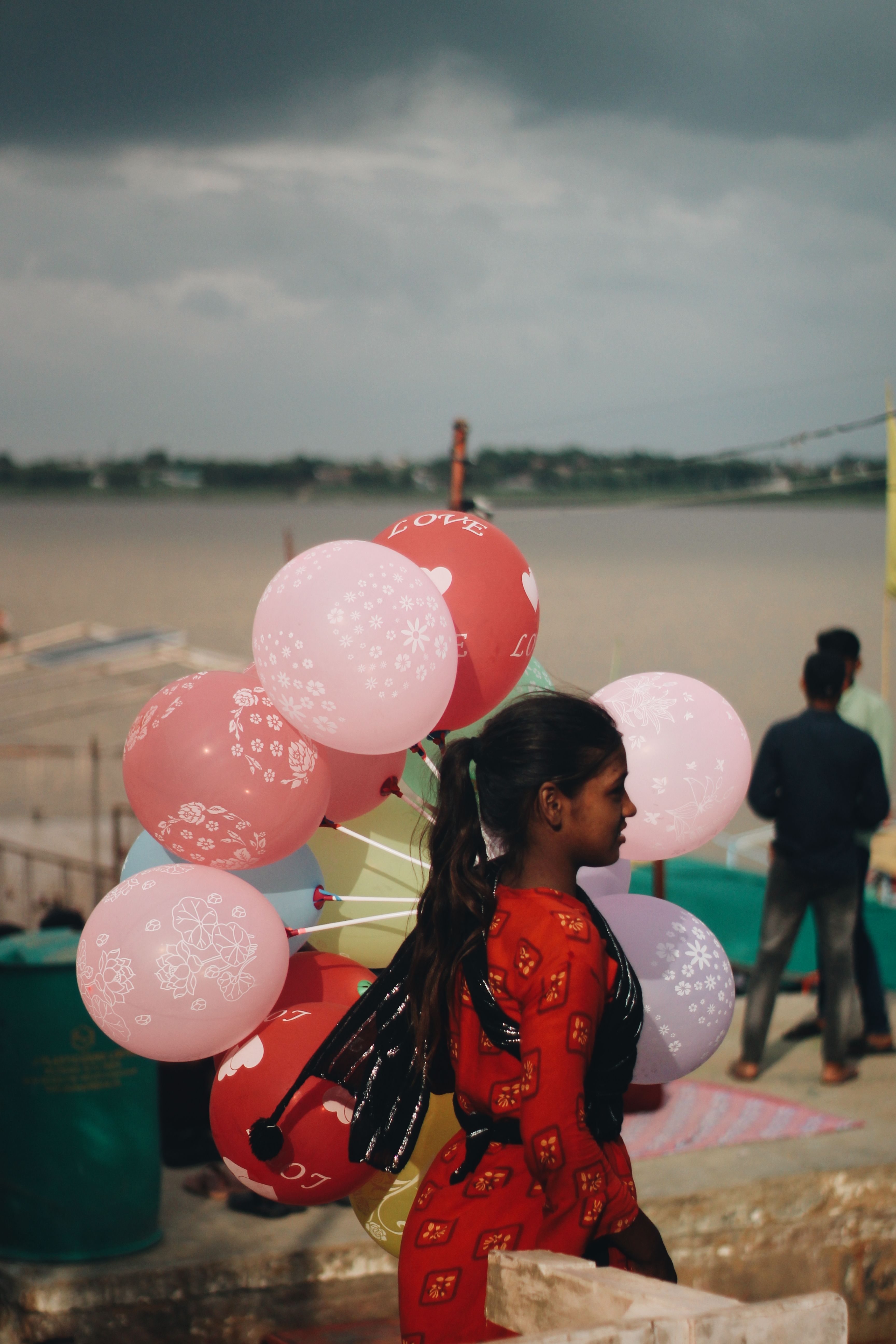 A woman carrying balloons on the river · Free Stock Photo