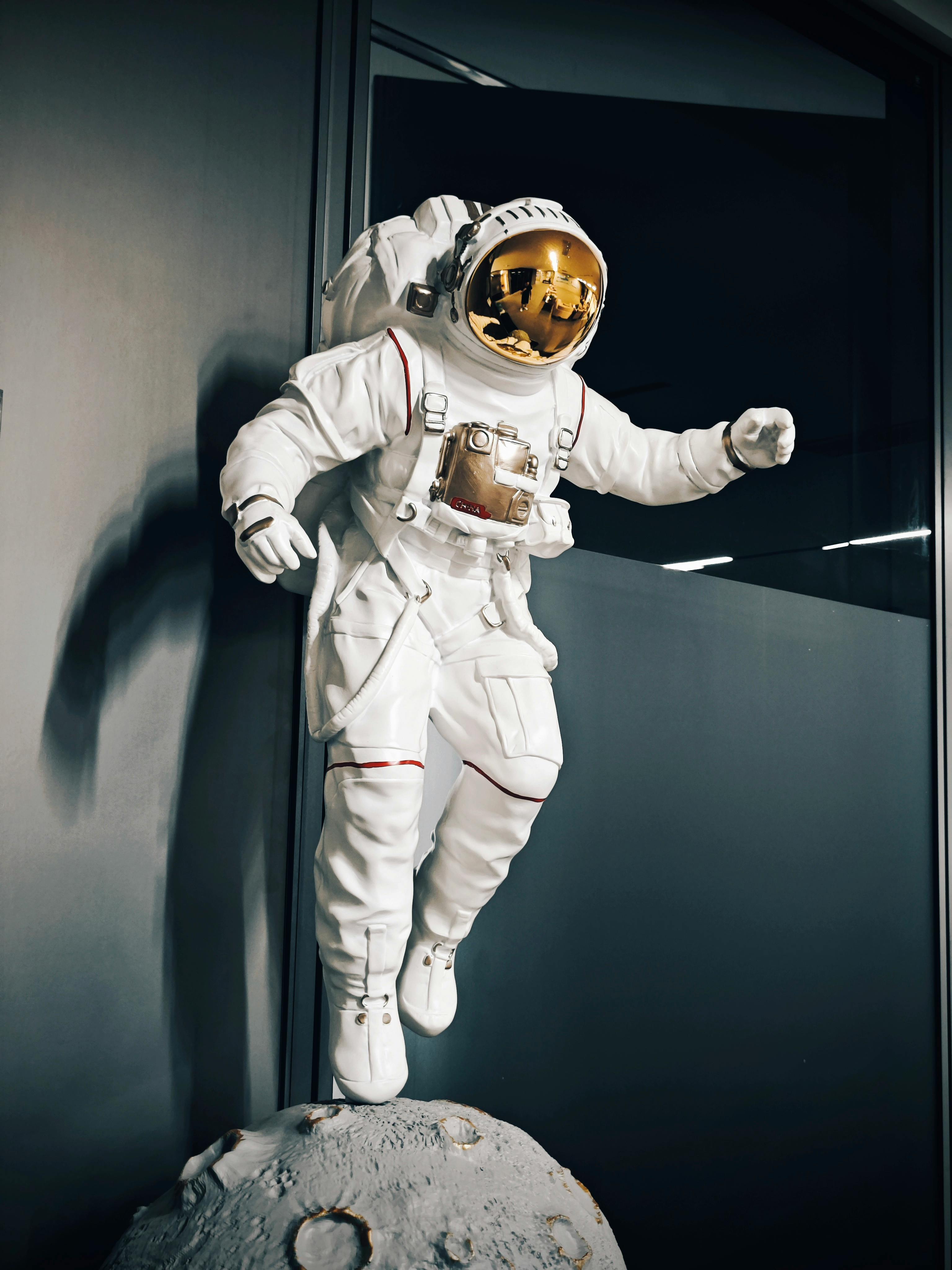 An astronaut statue is standing on a wall · Free Stock Photo