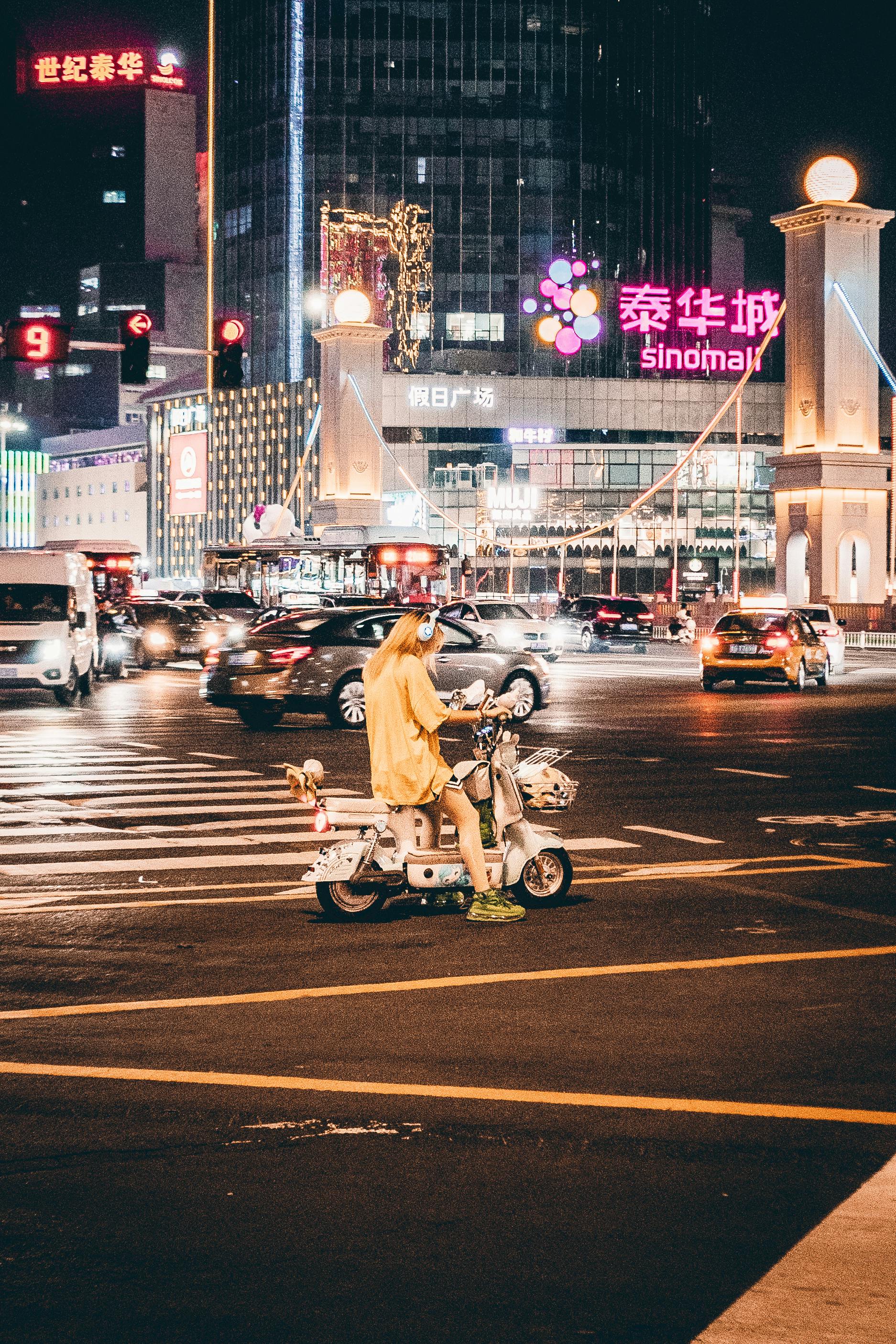 A person riding a scooter at night in a city · Free Stock Photo