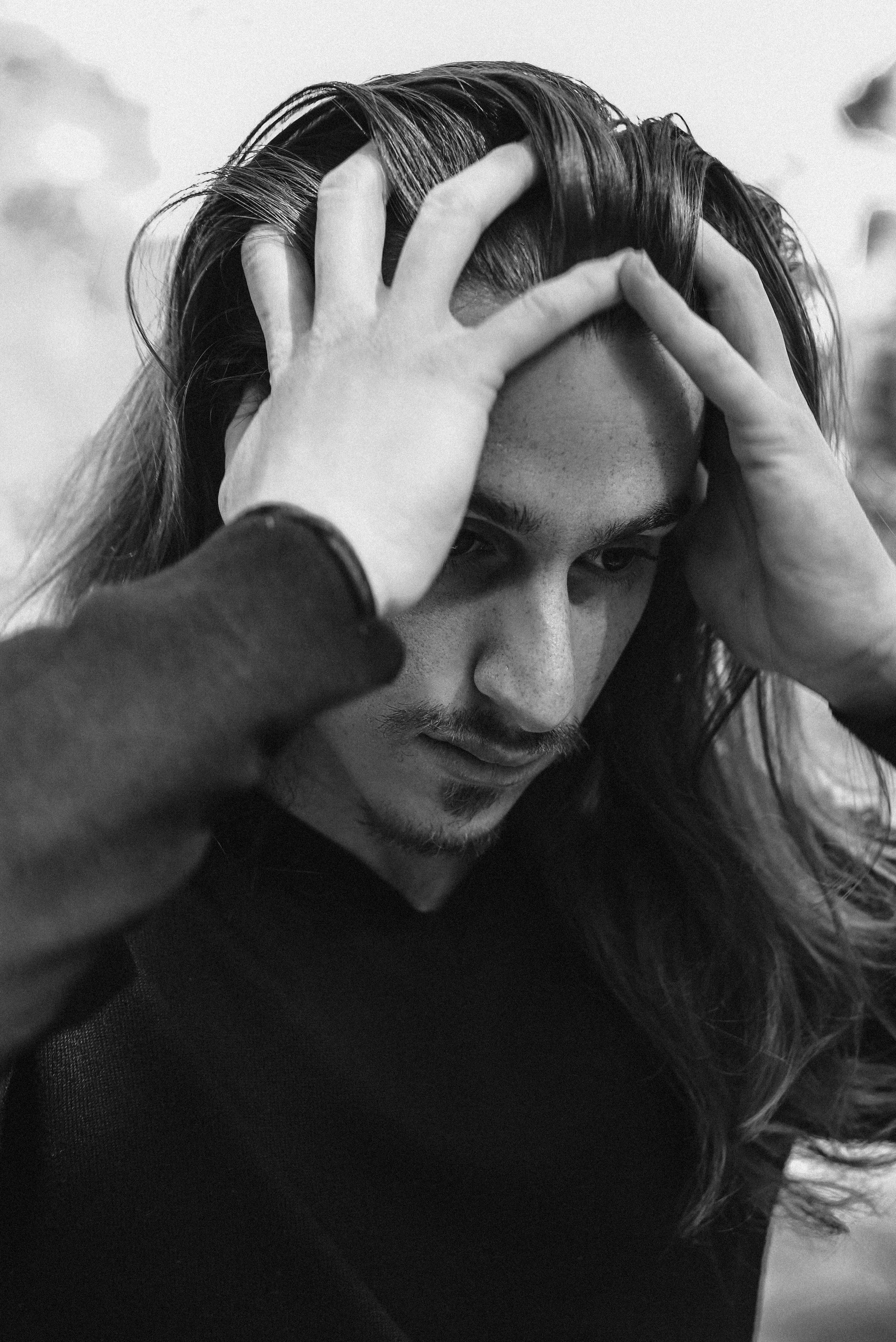 A man with long hair is holding his head · Free Stock Photo