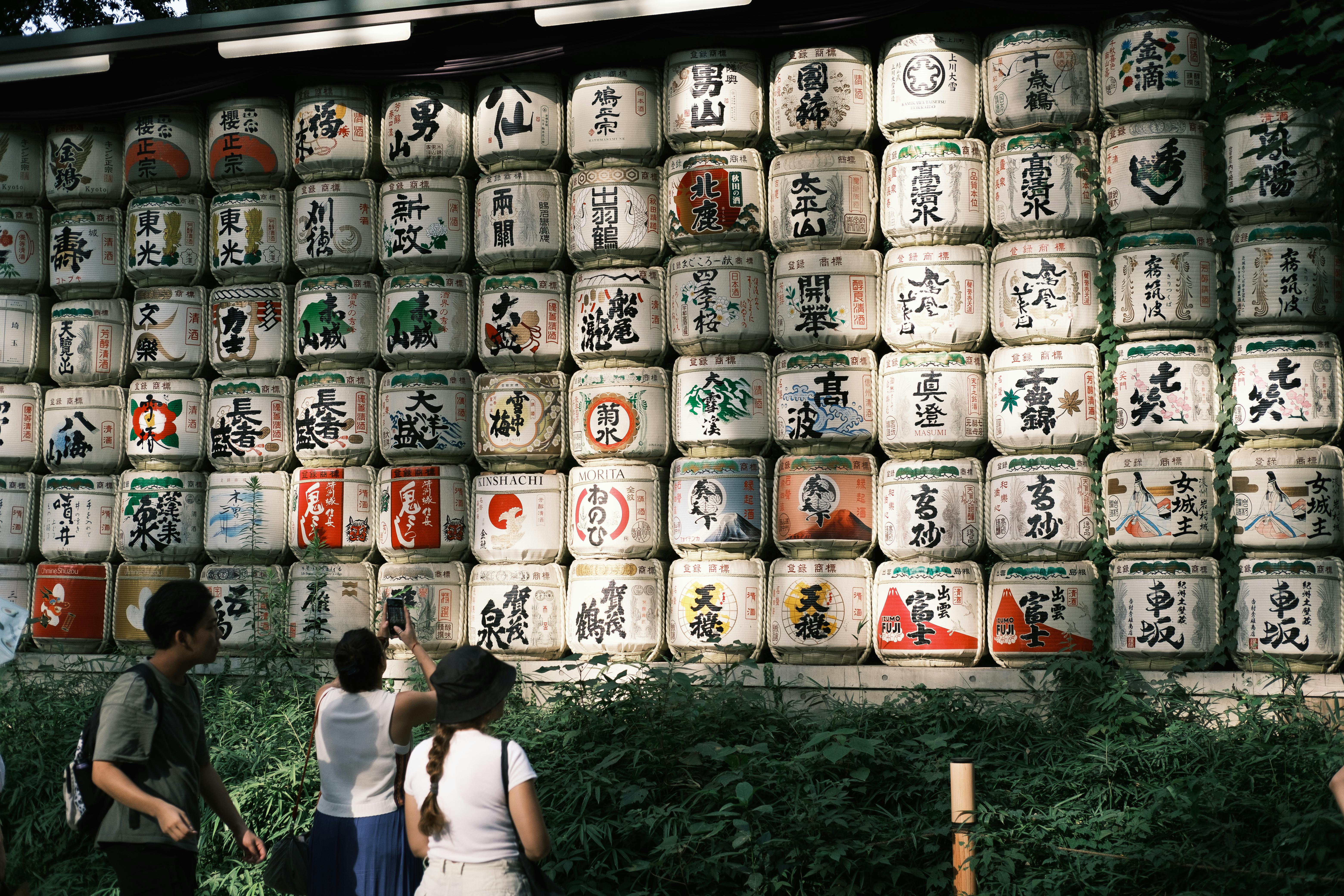A group of people standing in front of a wall of japanese writing ...