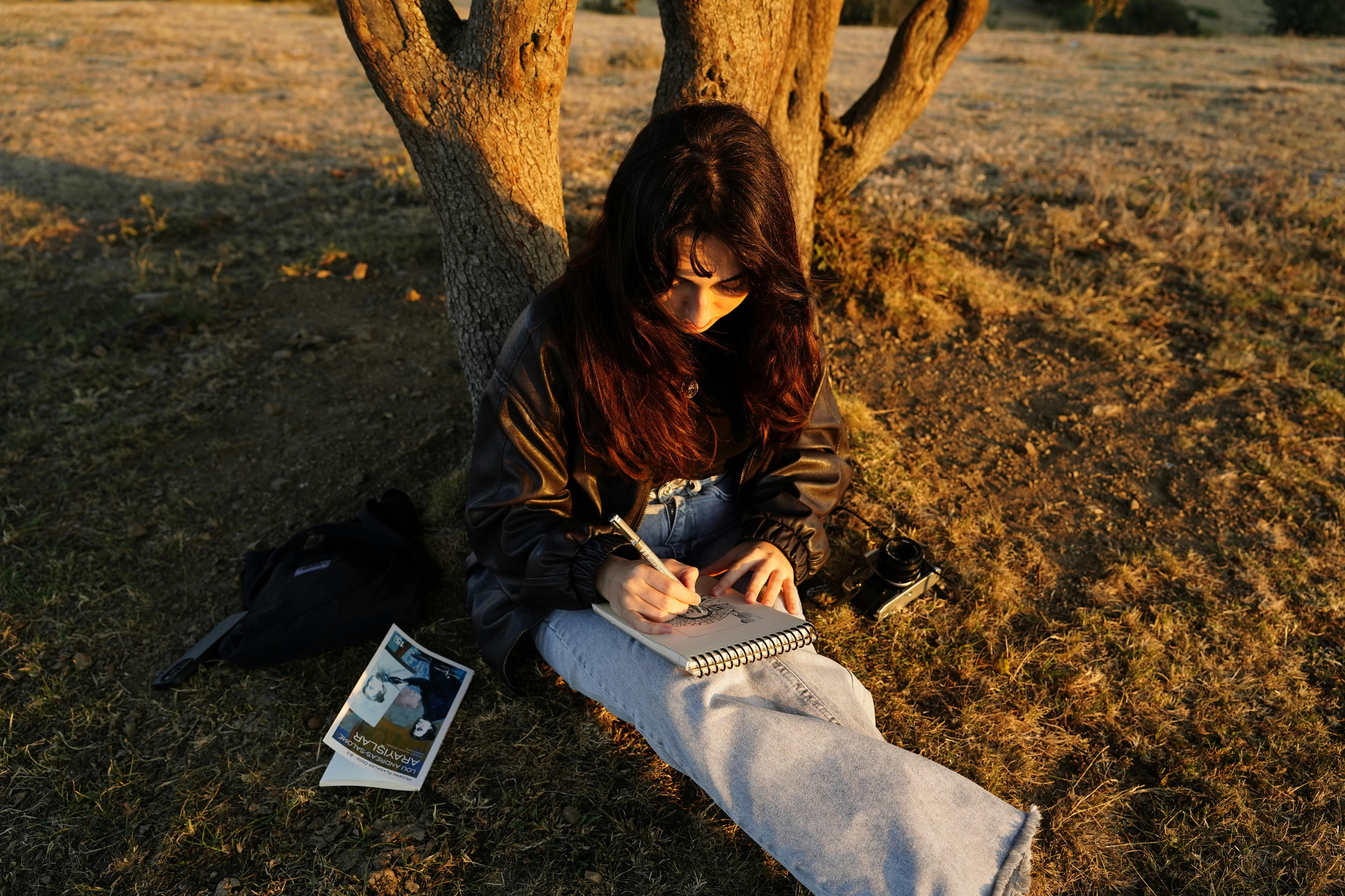 A woman sitting under a tree with a tablet · Free Stock Photo