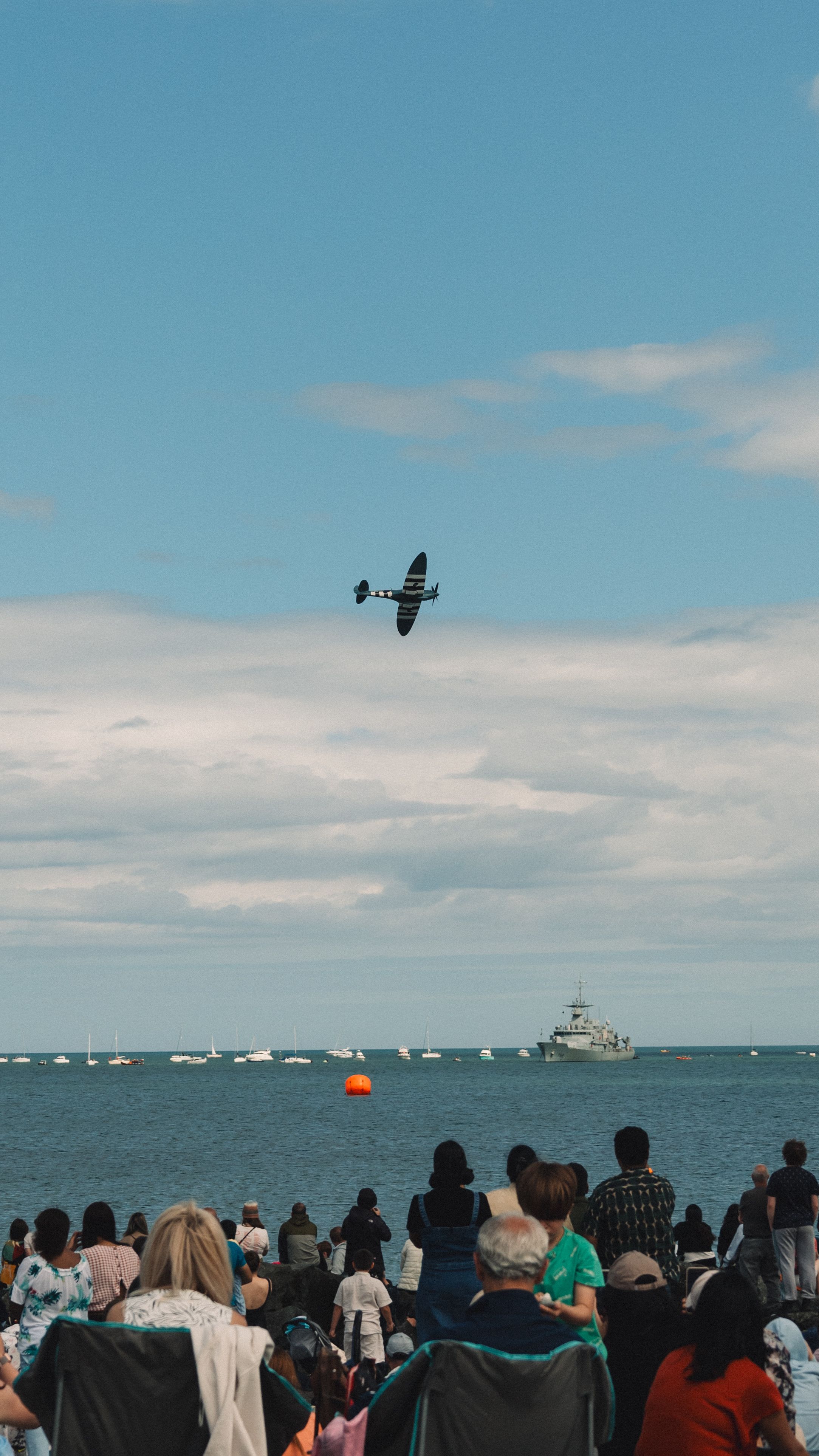 A plane flying over the ocean with people watching · Free Stock Photo
