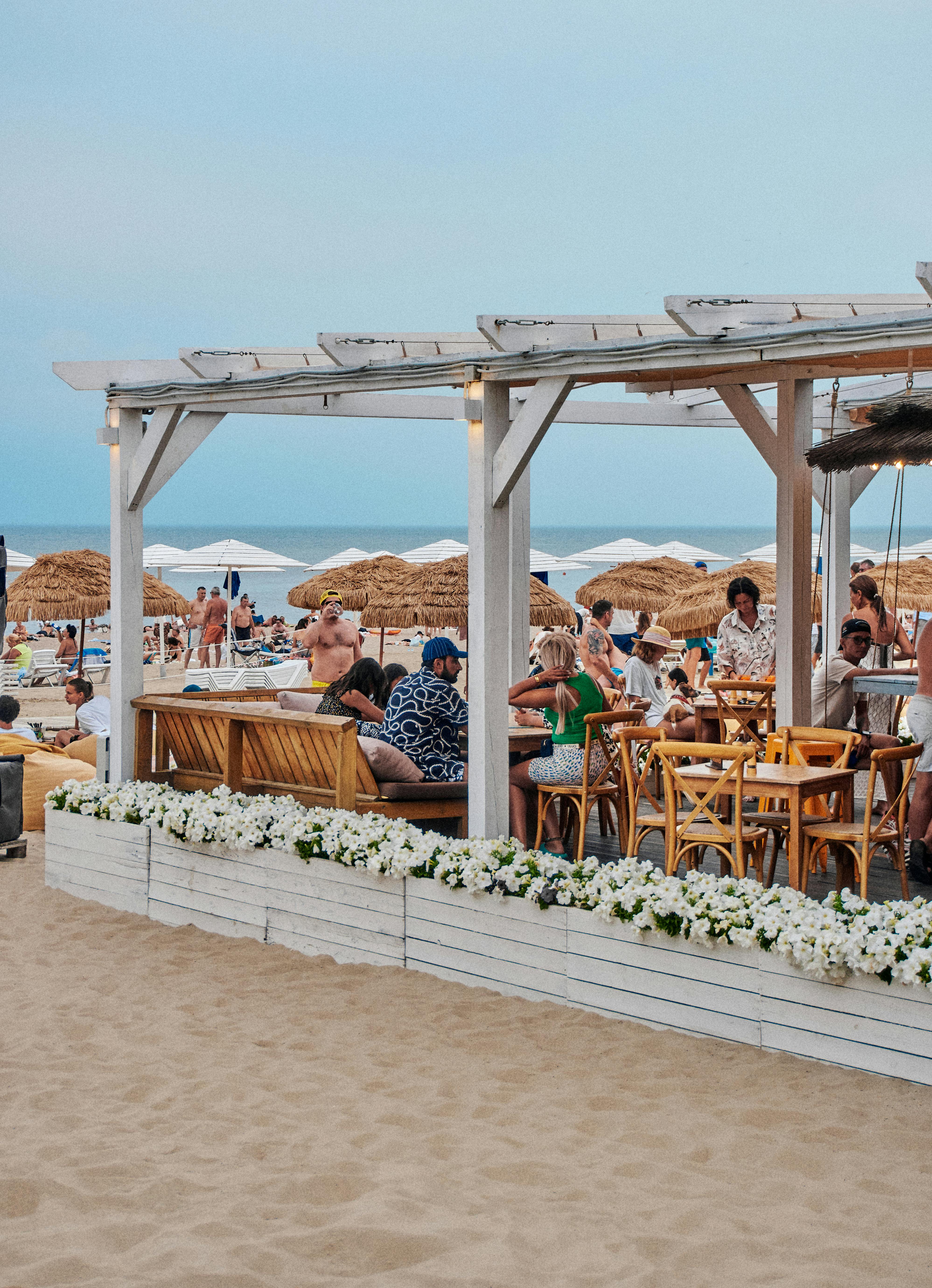 A beach bar with tables and chairs on the sand · Free Stock Photo