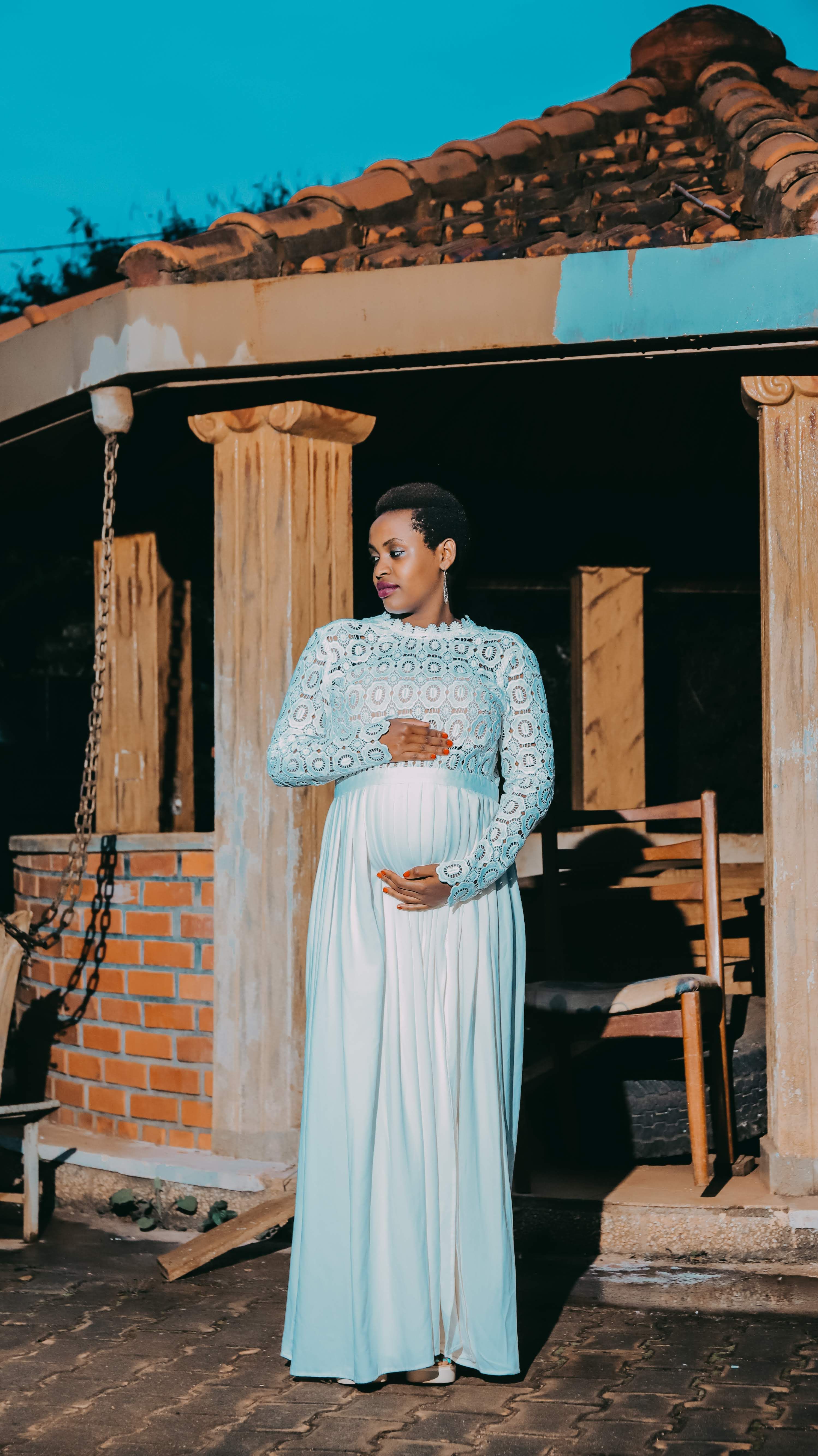 A pregnant woman in a white dress standing in front of a building ...
