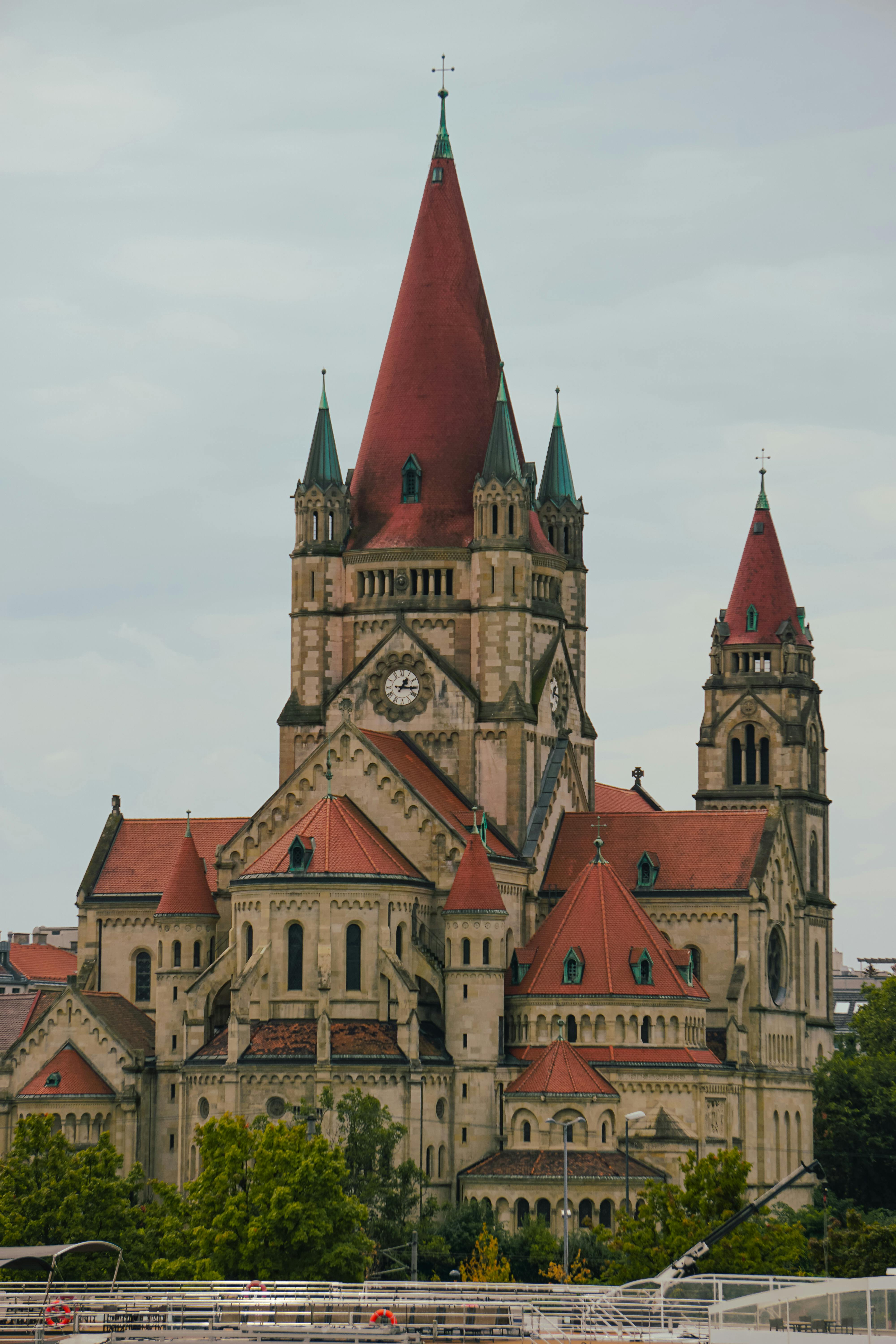 A large cathedral with red spires and a clock tower · Free Stock Photo