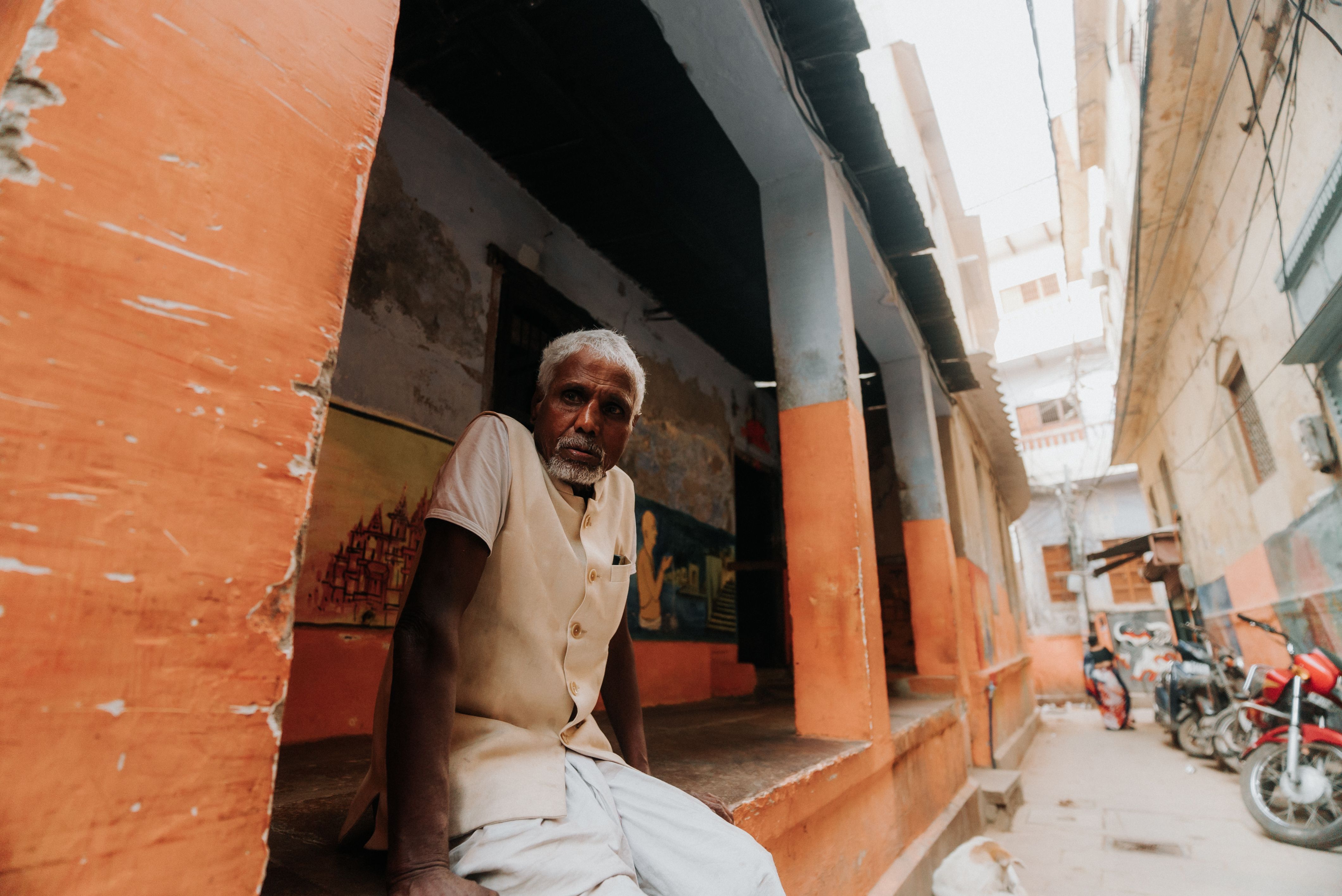 An old man sitting on the side of a building · Free Stock Photo