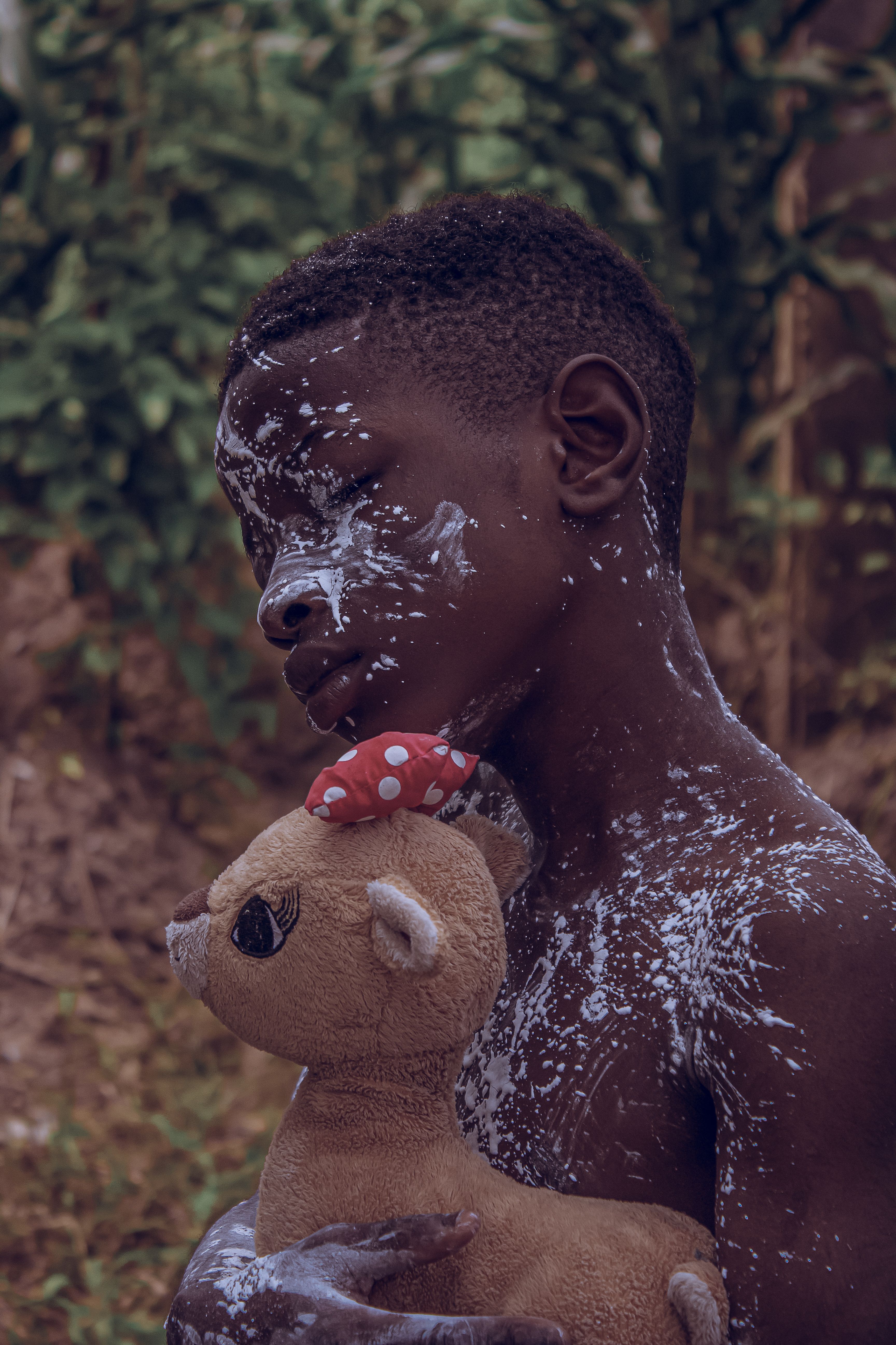 A young boy with white paint on his face holding a stuffed animal ...
