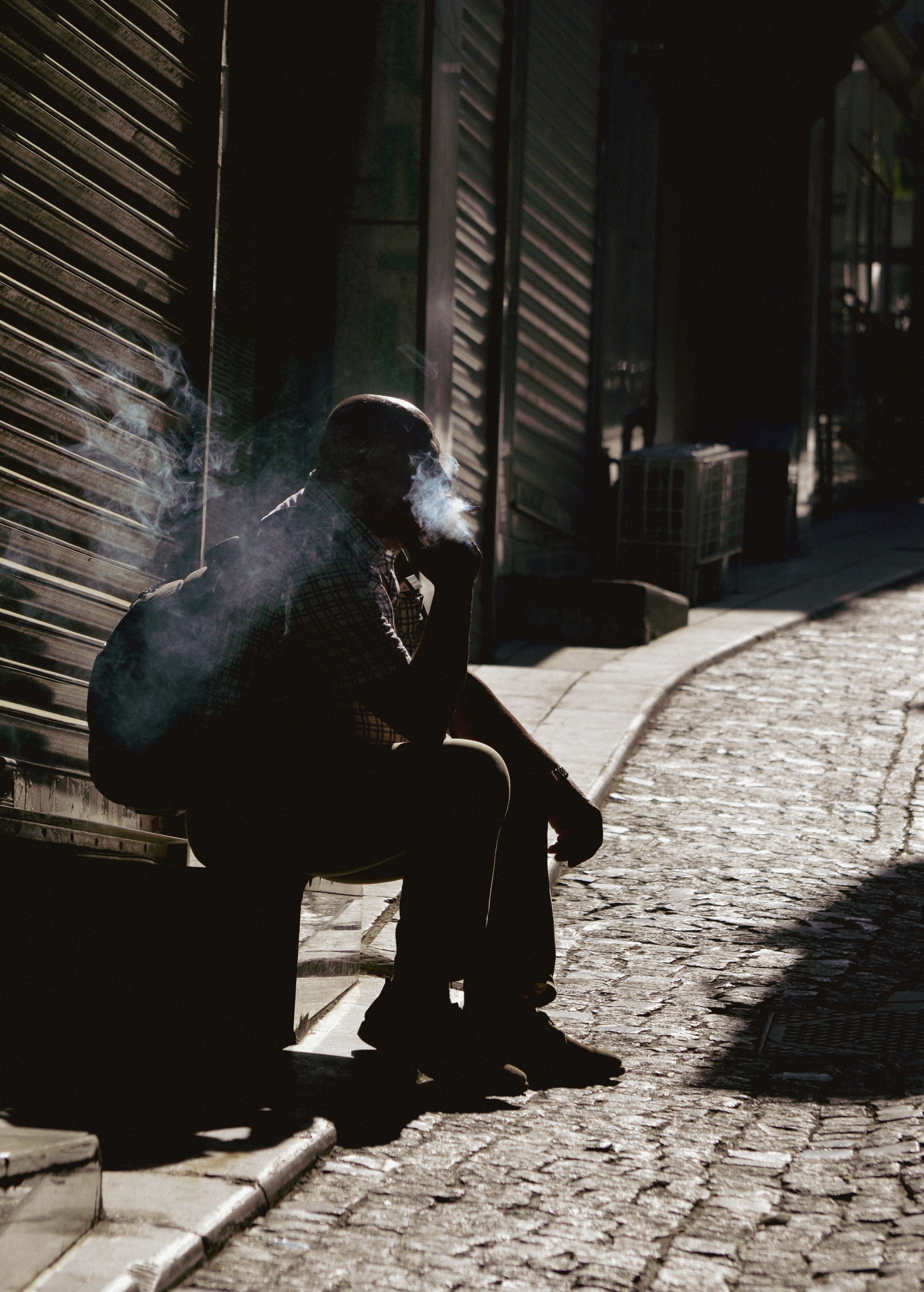A man sitting on a bench smoking a cigarette · Free Stock Photo