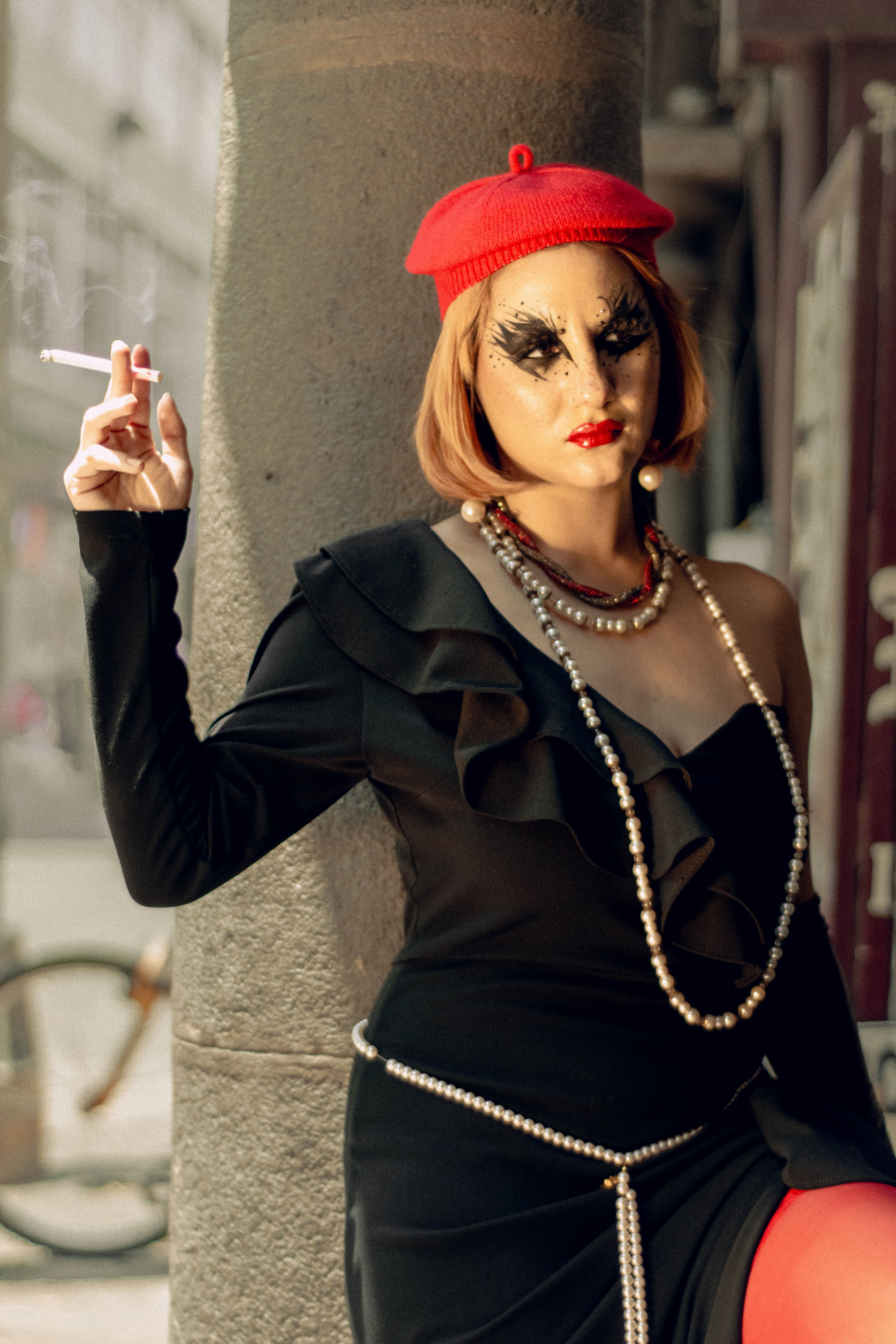 A woman in a red beret and black dress smoking a cigarette · Free Stock ...