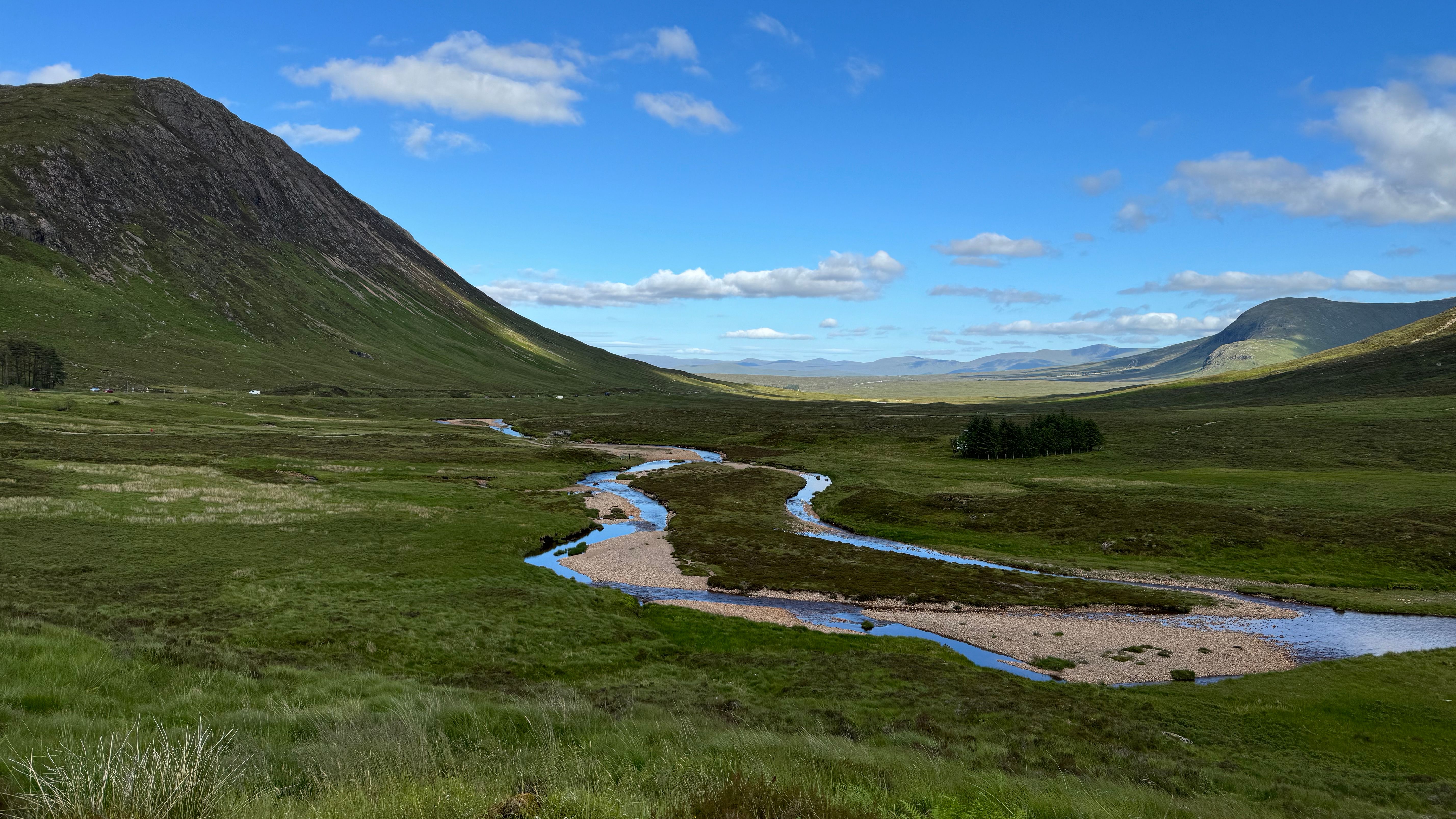 A river runs through a grassy valley in the scottish highlands · Free ...