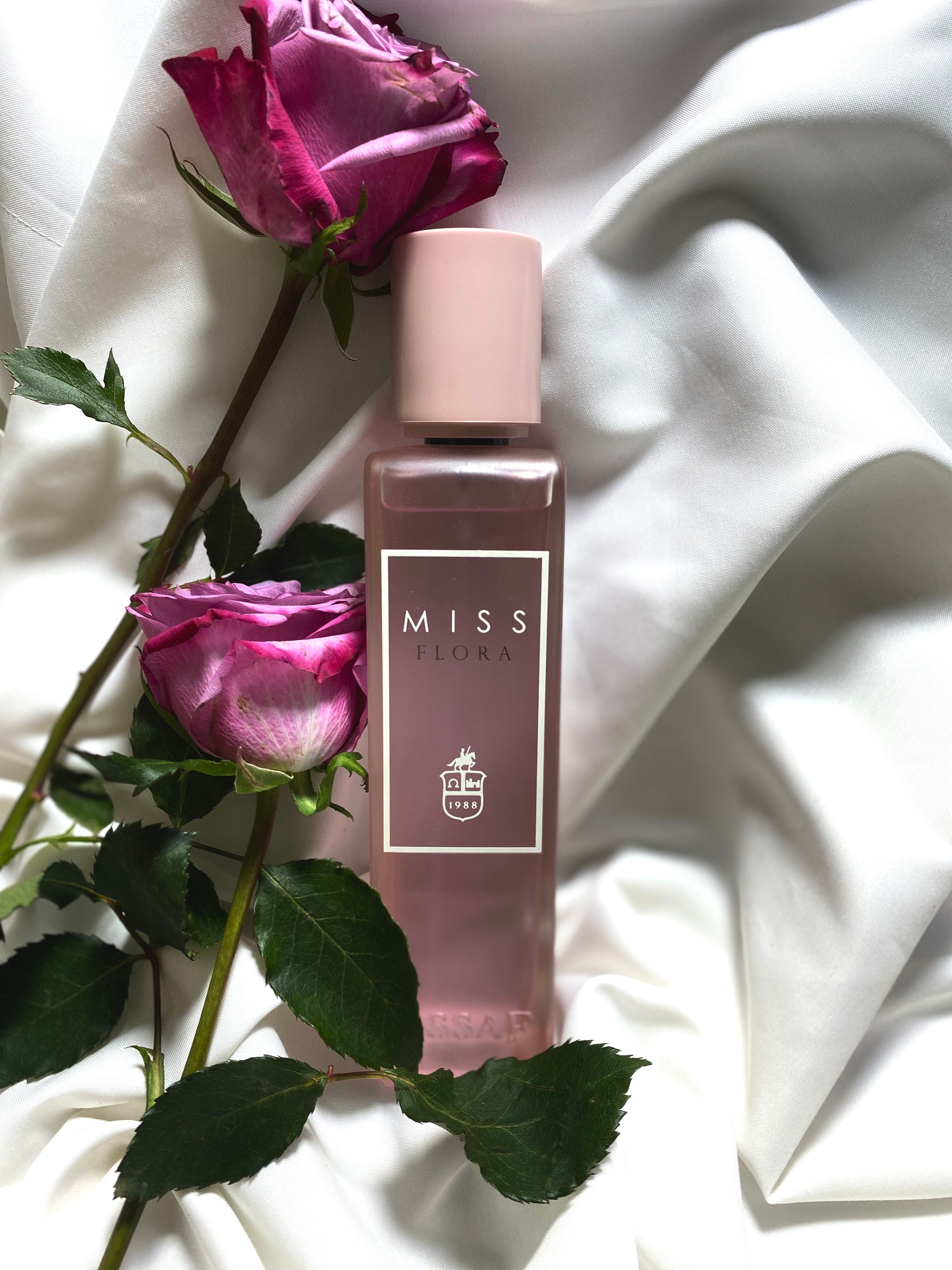 Miss perfume on a white cloth with pink roses · Free Stock Photo