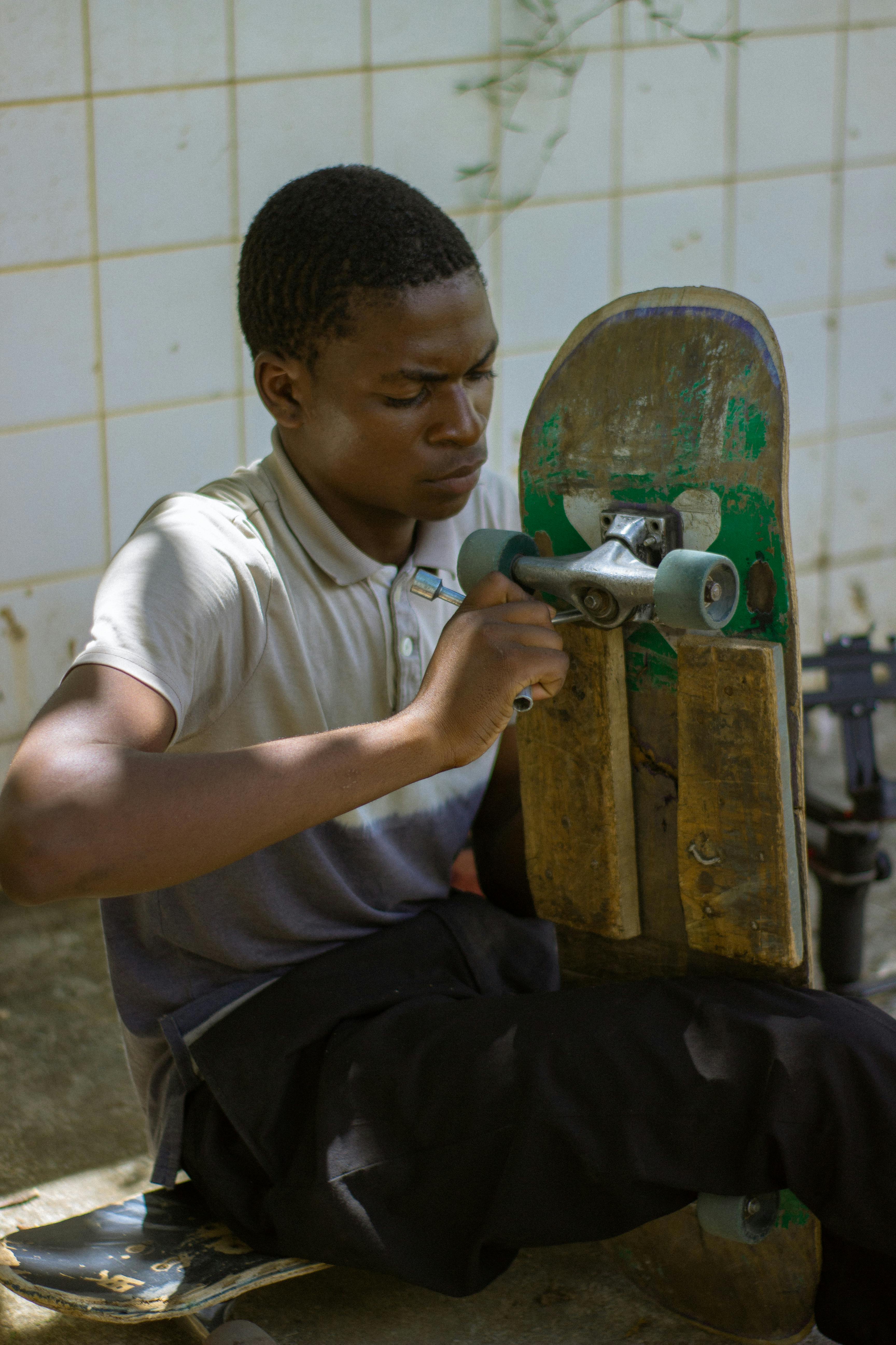 Determined young African man Fixing His Skateboard. Malawian skater ...