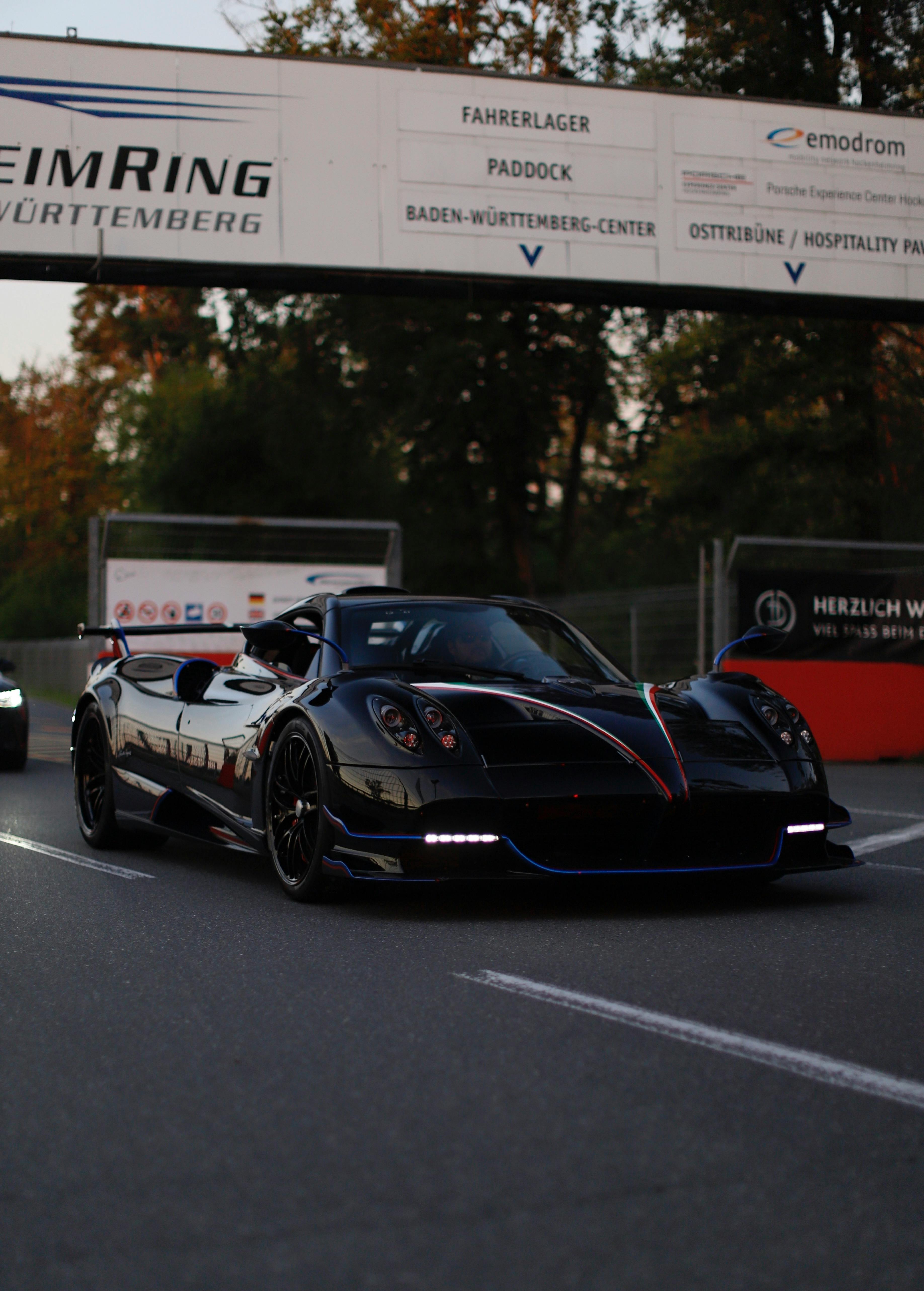 A black sports car driving down a road · Free Stock Photo