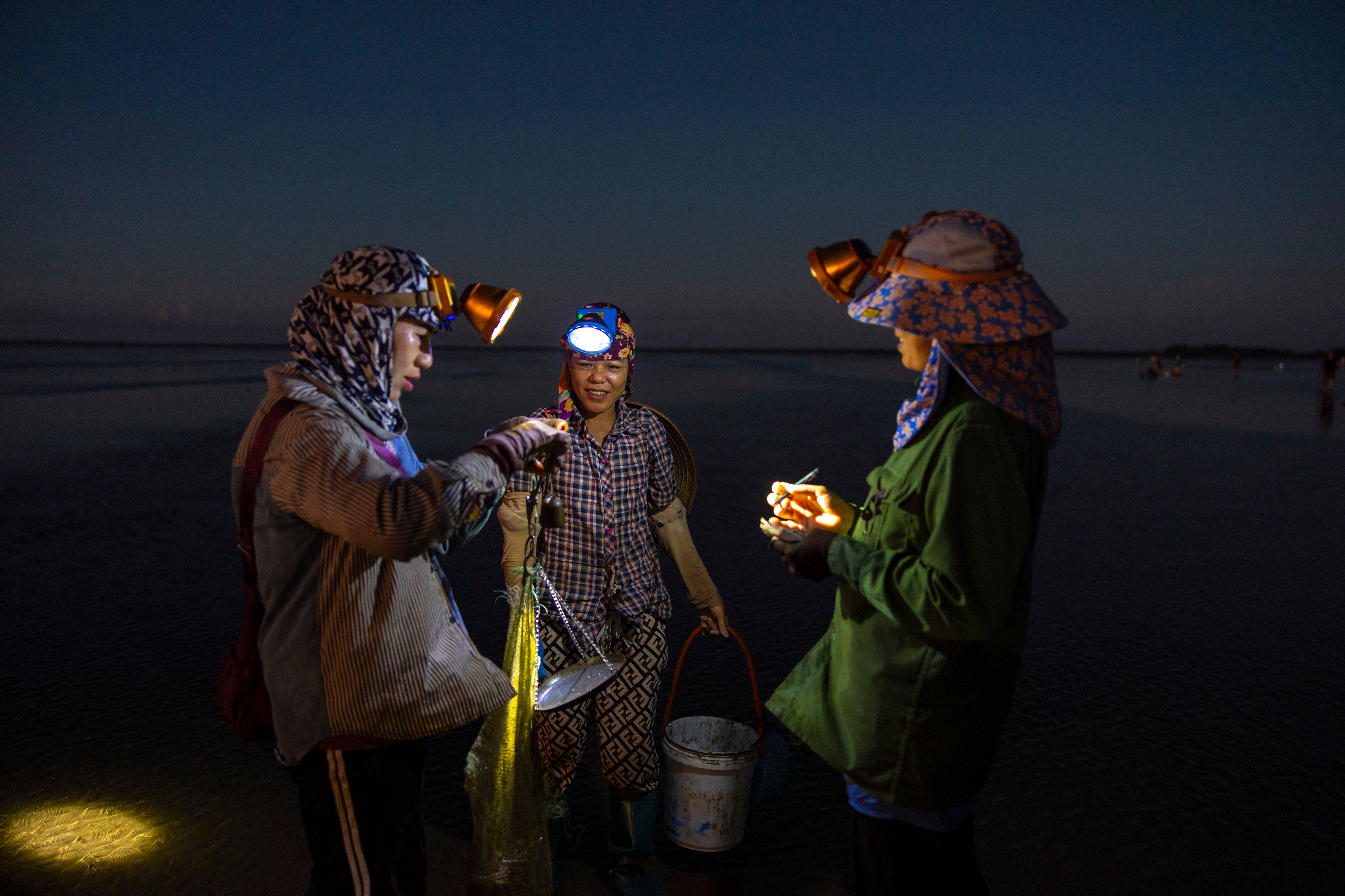 Three people standing on the beach holding food · Free Stock Photo