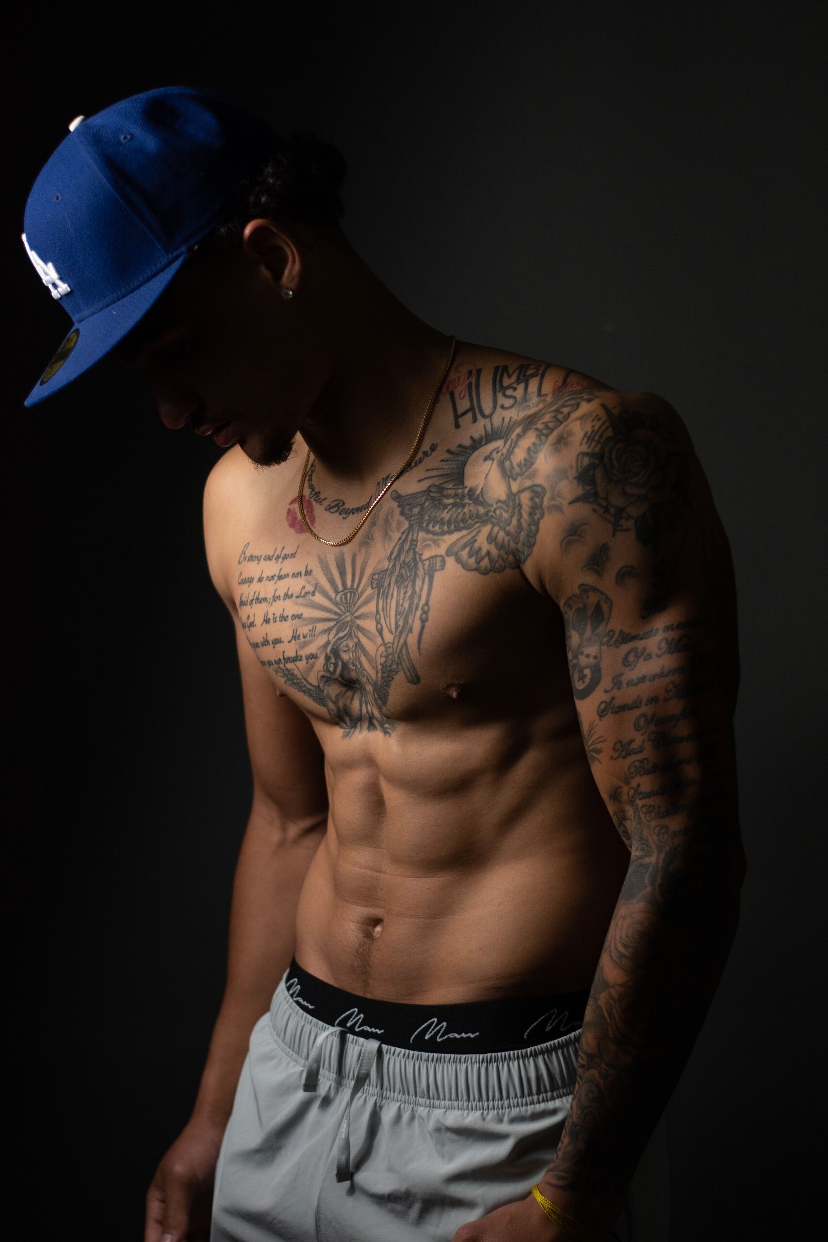 A shirtless man with tattoos and a blue hat · Free Stock Photo