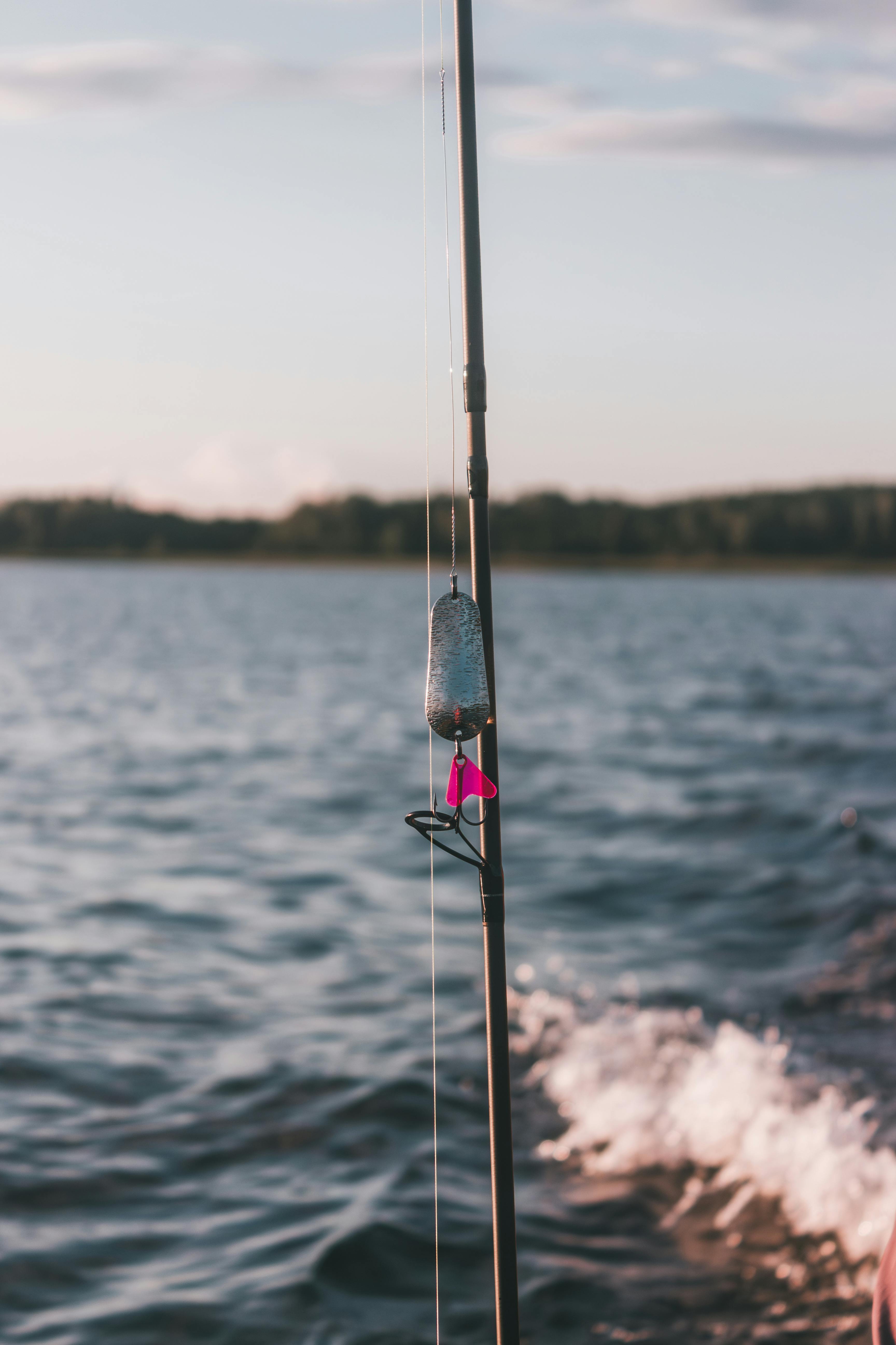A fishing rod on the water with a pink fishing pole · Free Stock Photo