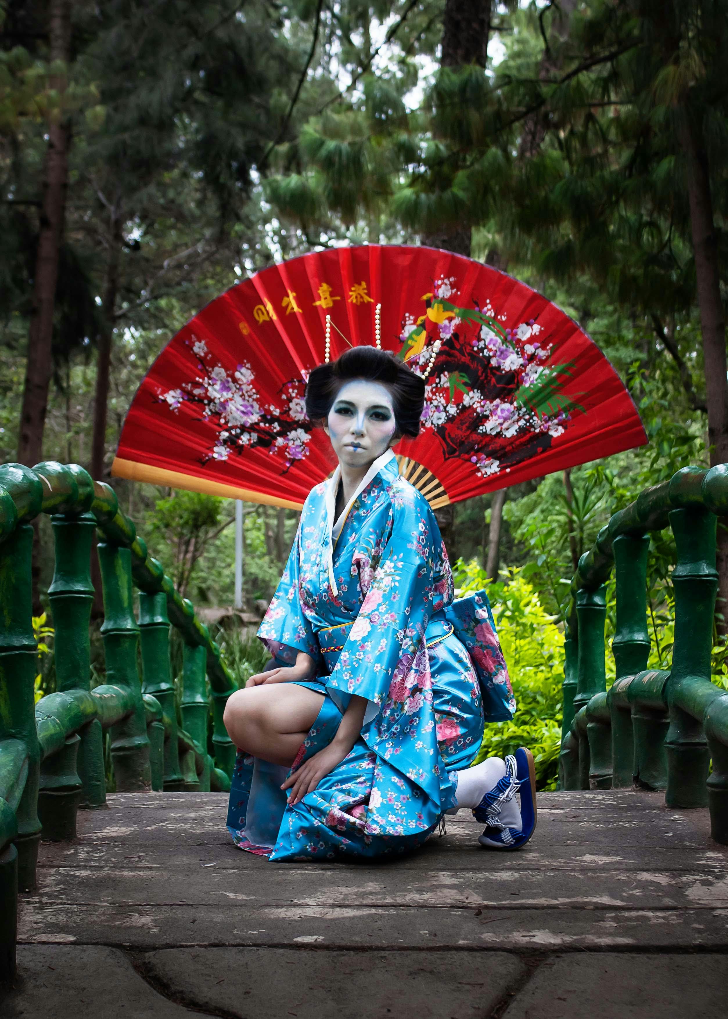 A woman in a geisha costume sitting on a bridge · Free Stock Photo