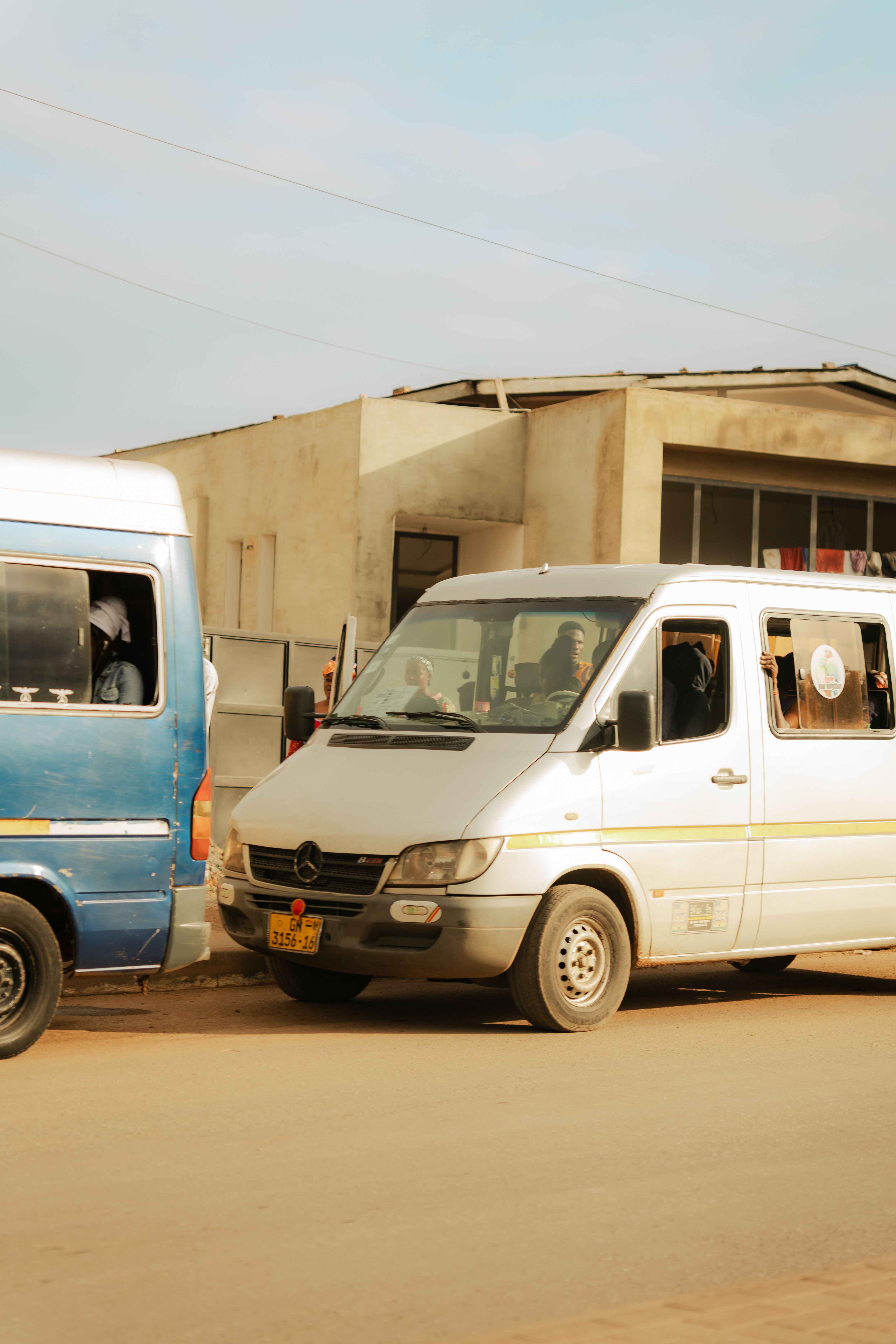 A white van and a blue van are parked next to each other · Free Stock Photo