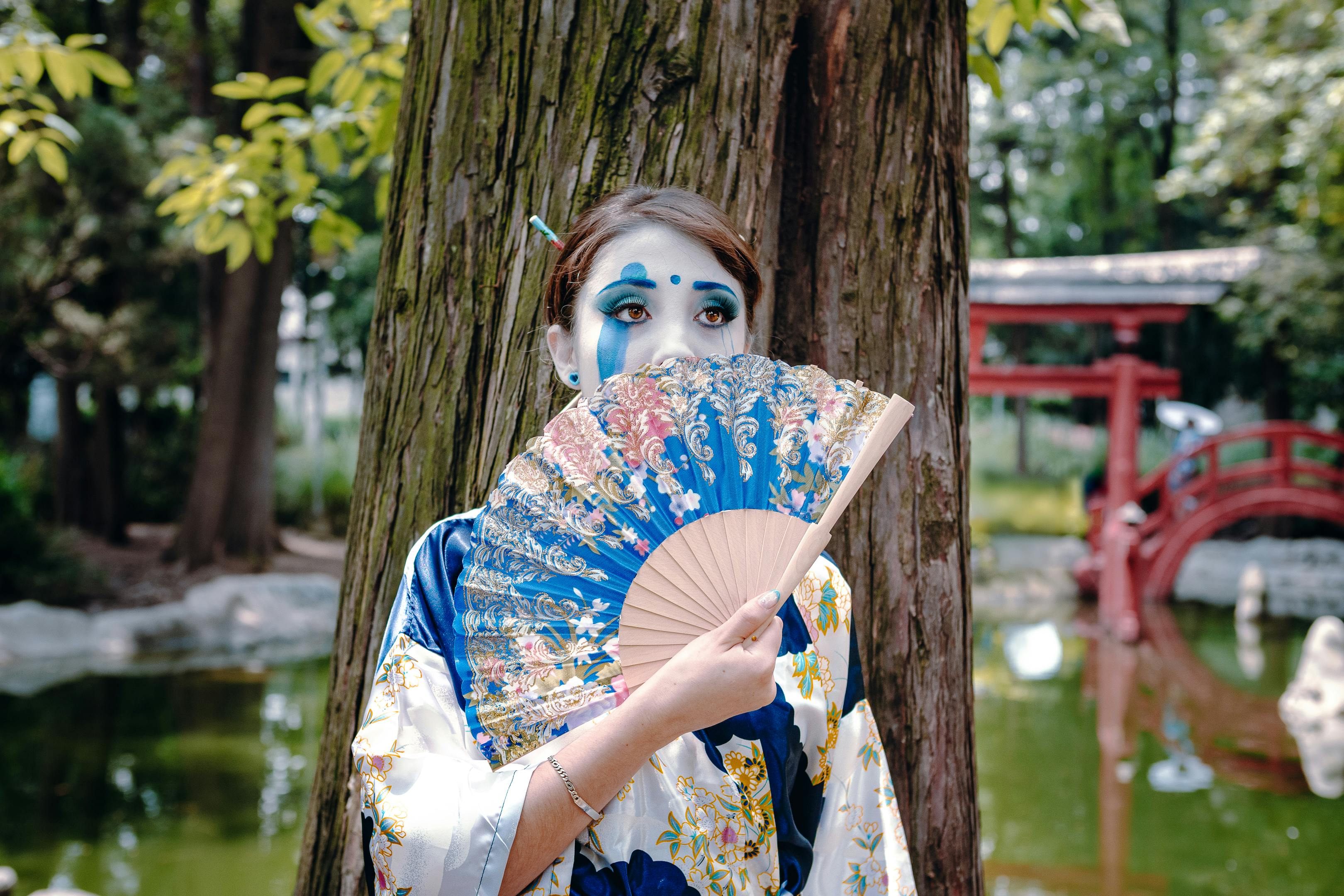 A woman in a geisha costume holding a fan · Free Stock Photo
