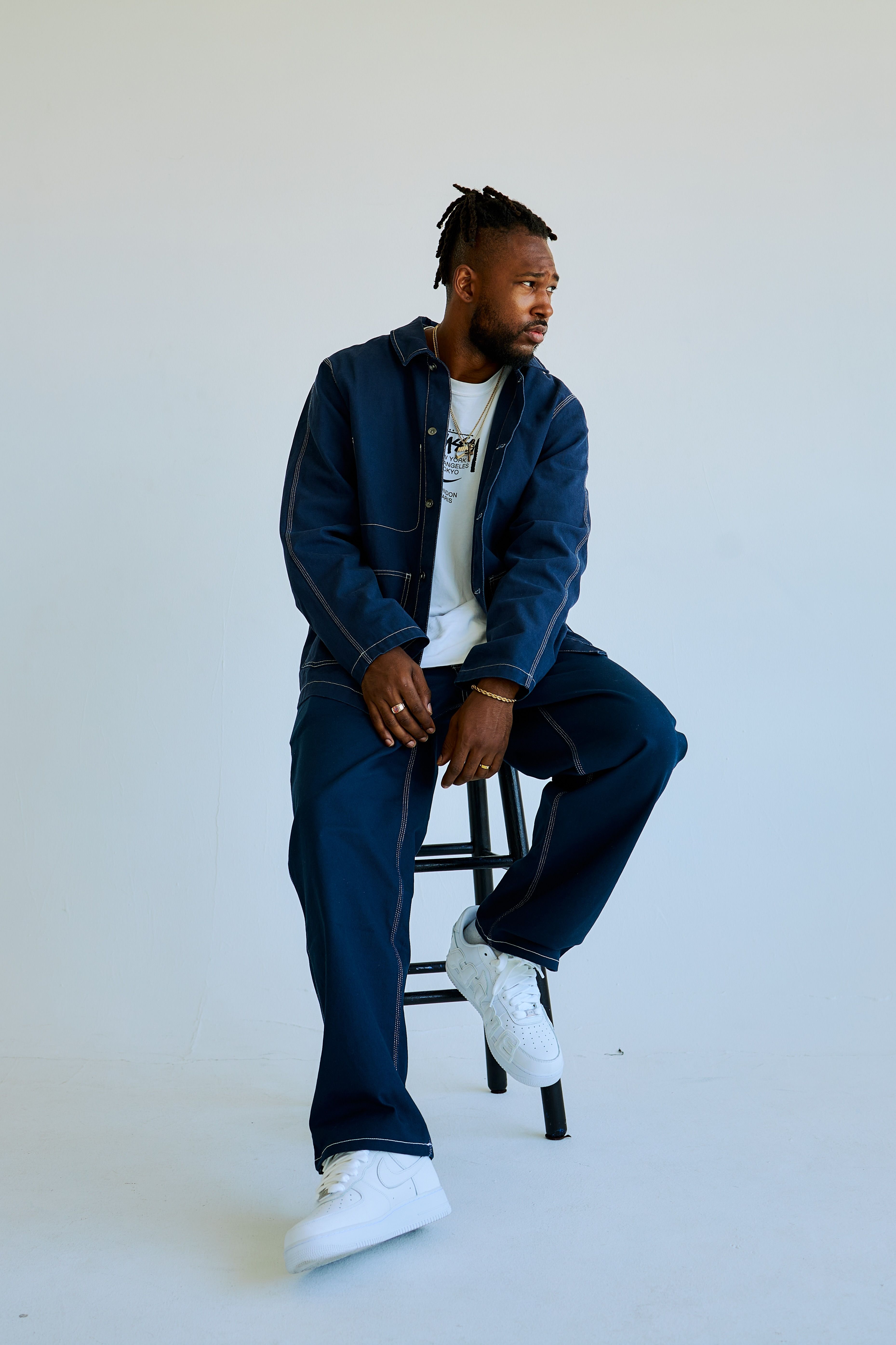 A man in a denim jacket sitting on a stool · Free Stock Photo