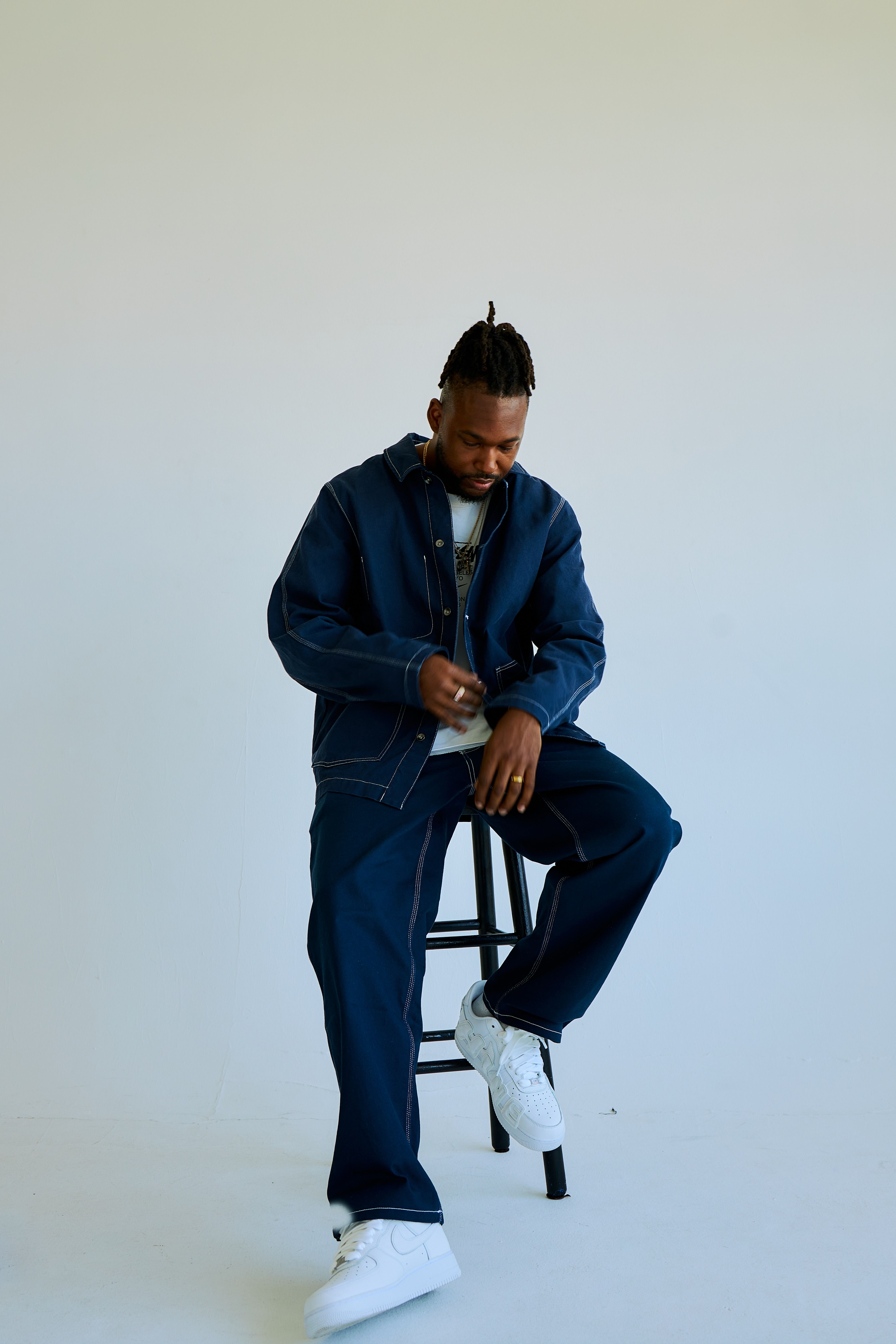 A man sitting on a stool wearing a denim jacket · Free Stock Photo