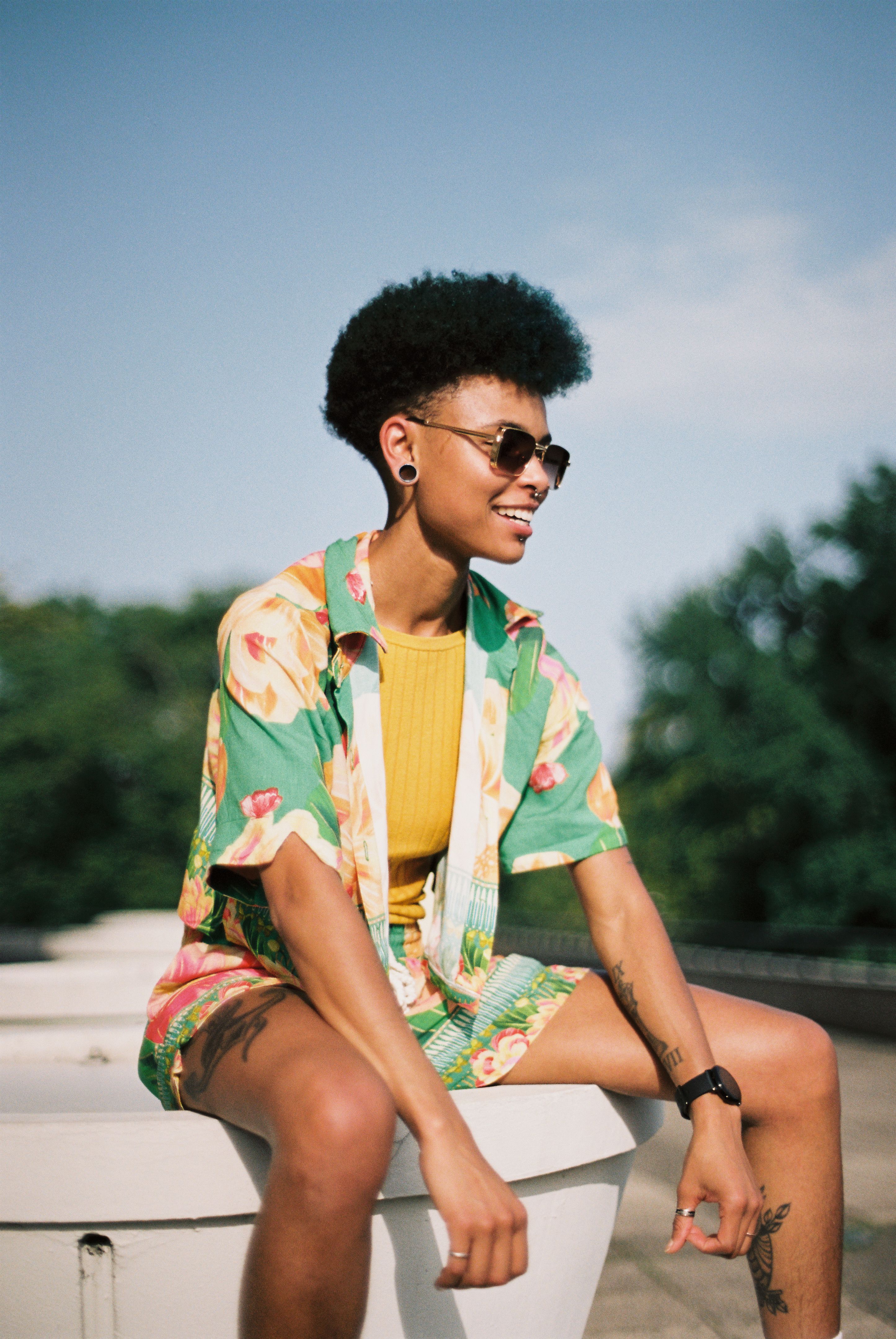 A woman with an afro sitting on a bench · Free Stock Photo