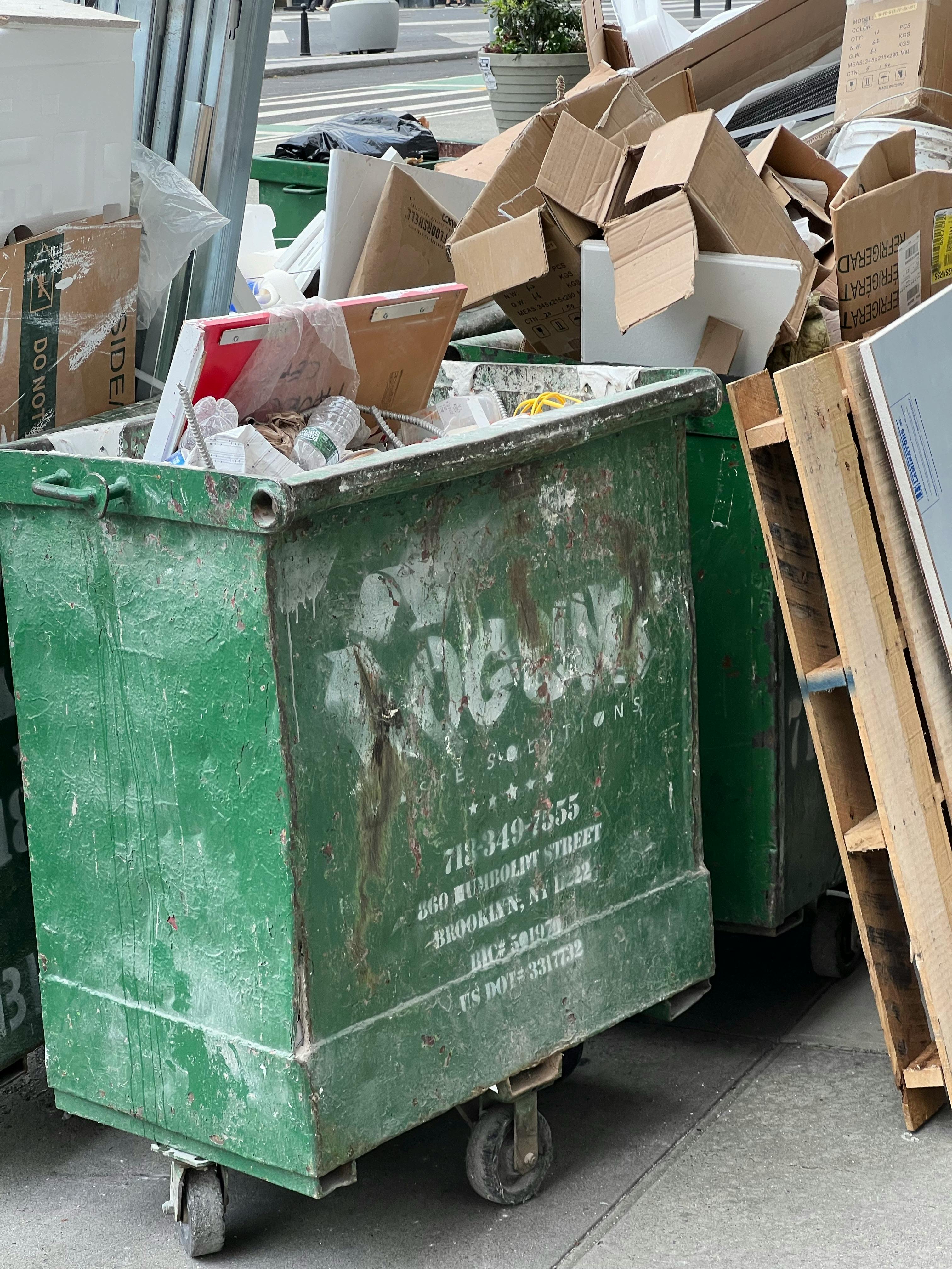 A green trash can with cardboard boxes in it · Free Stock Photo