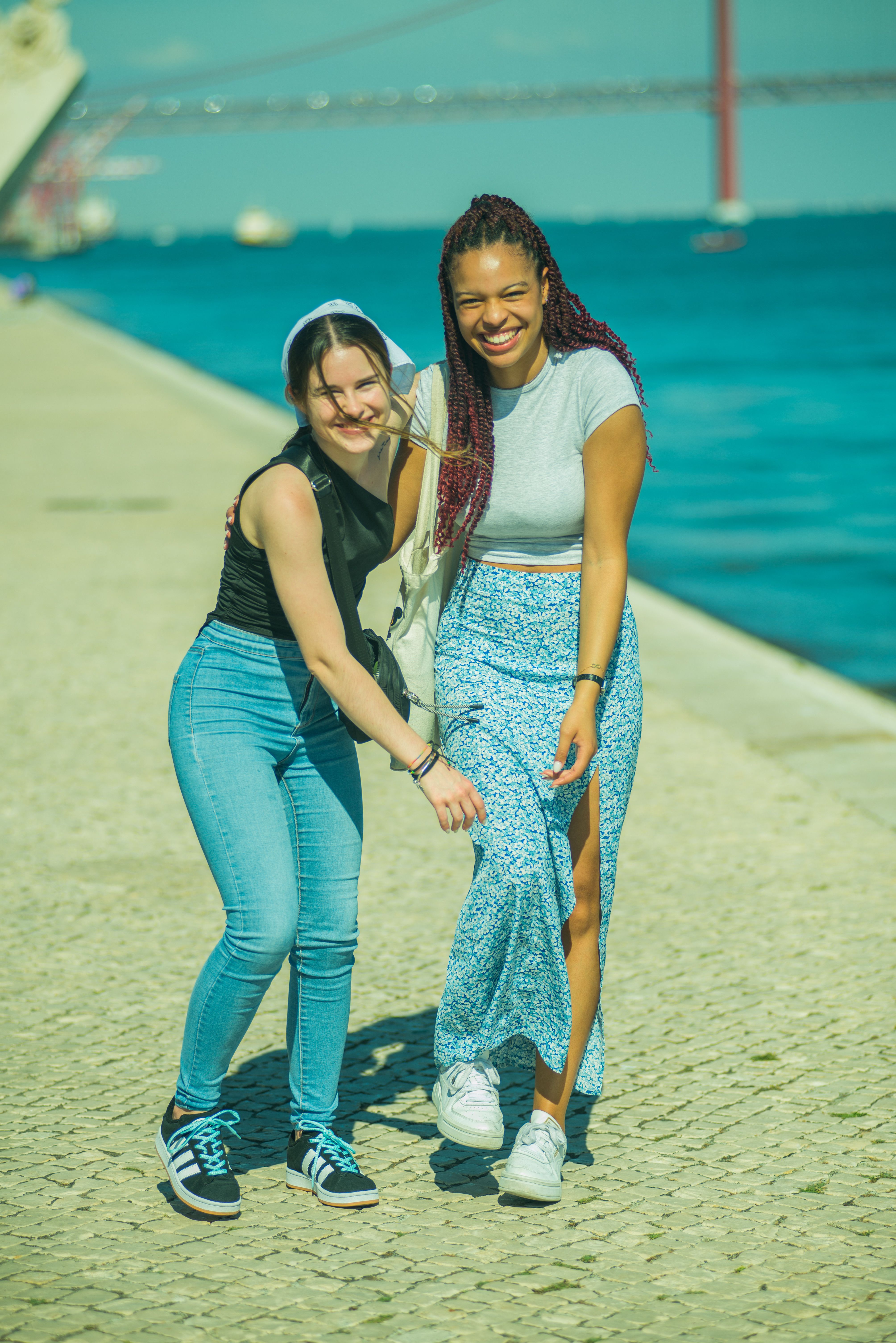 Two women standing next to each other on a sidewalk · Free Stock Photo