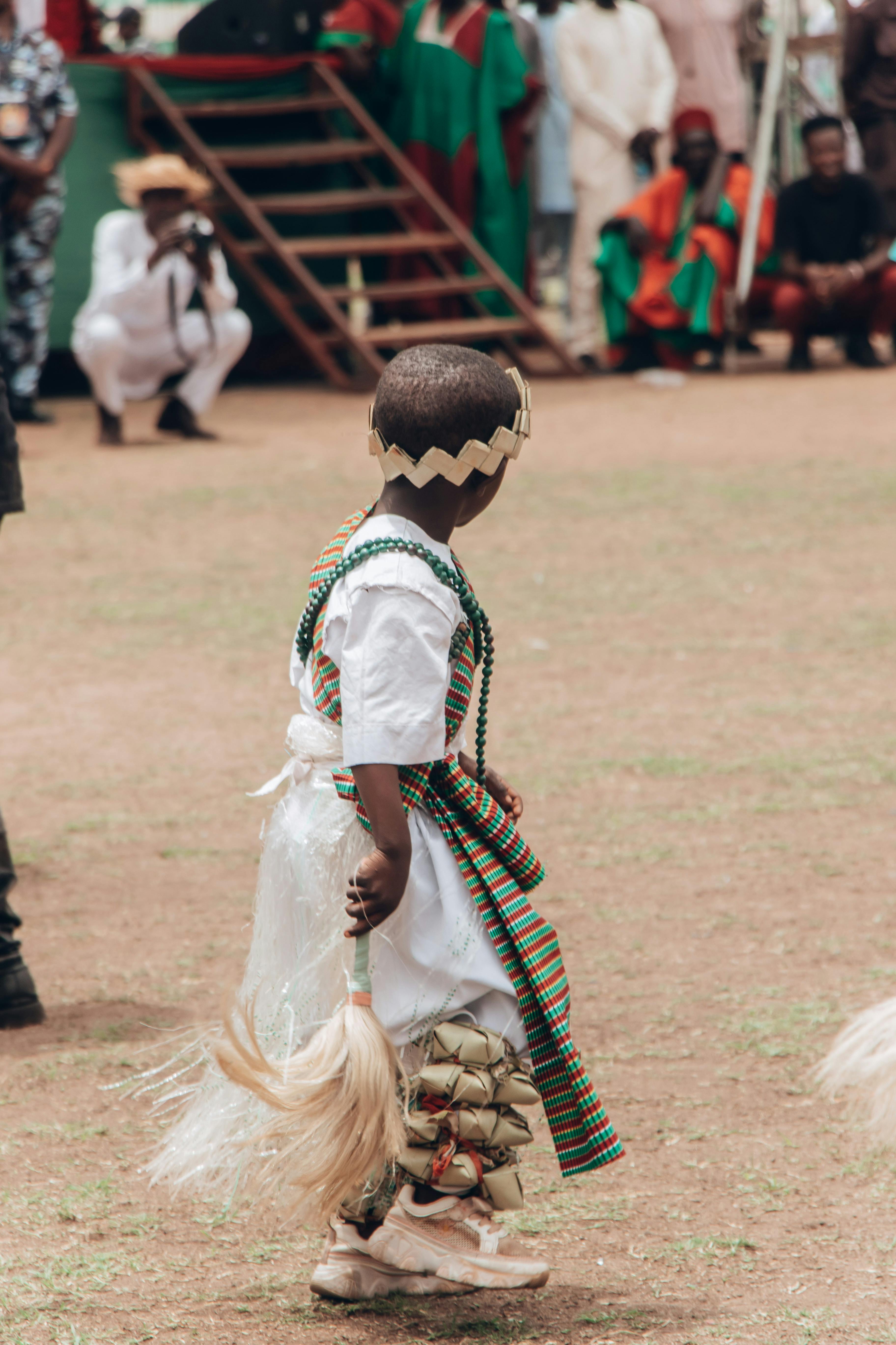 A young boy in traditional dress walking on the ground · Free Stock Photo