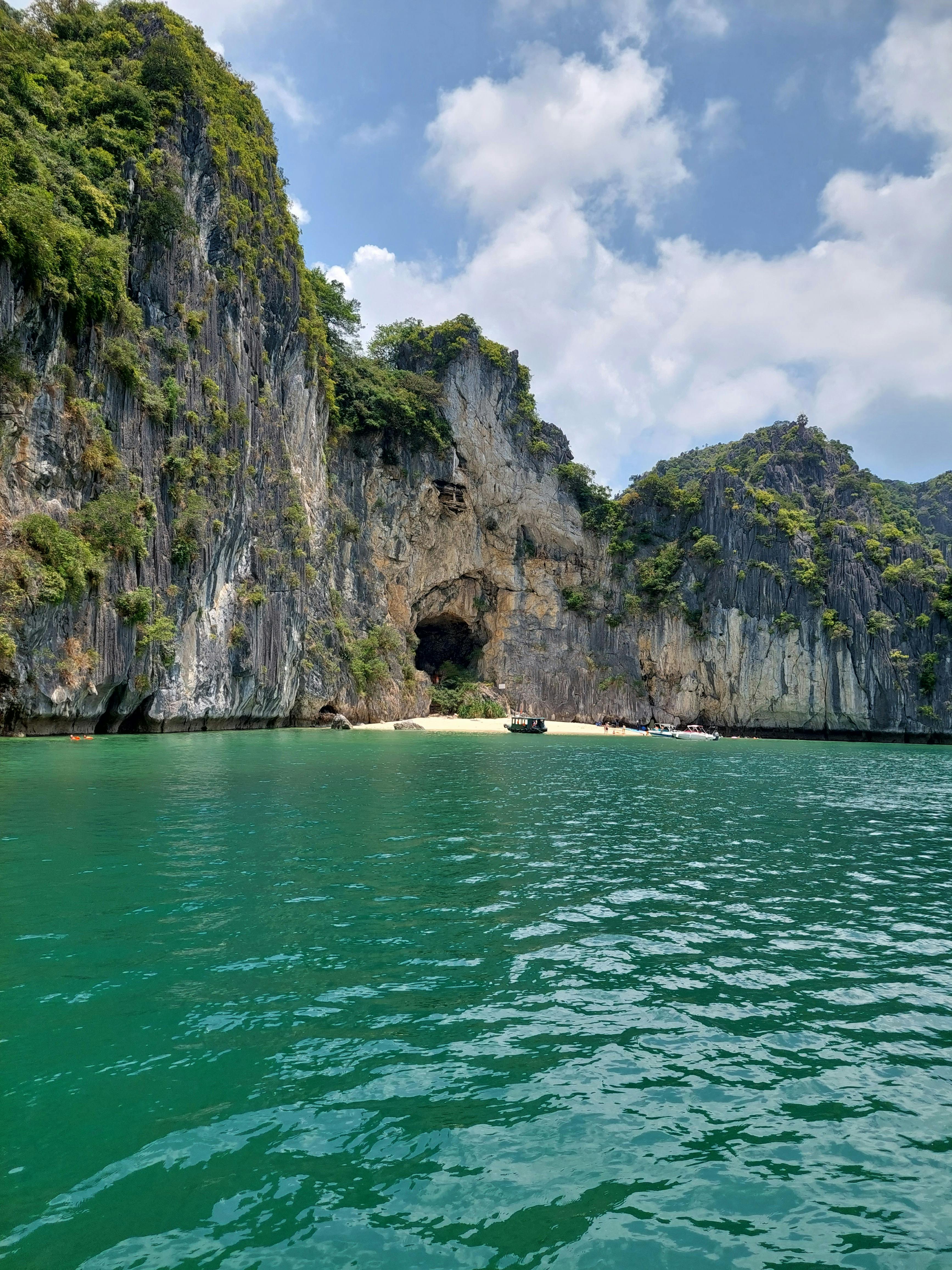 A boat is in the water near a cliff · Free Stock Photo