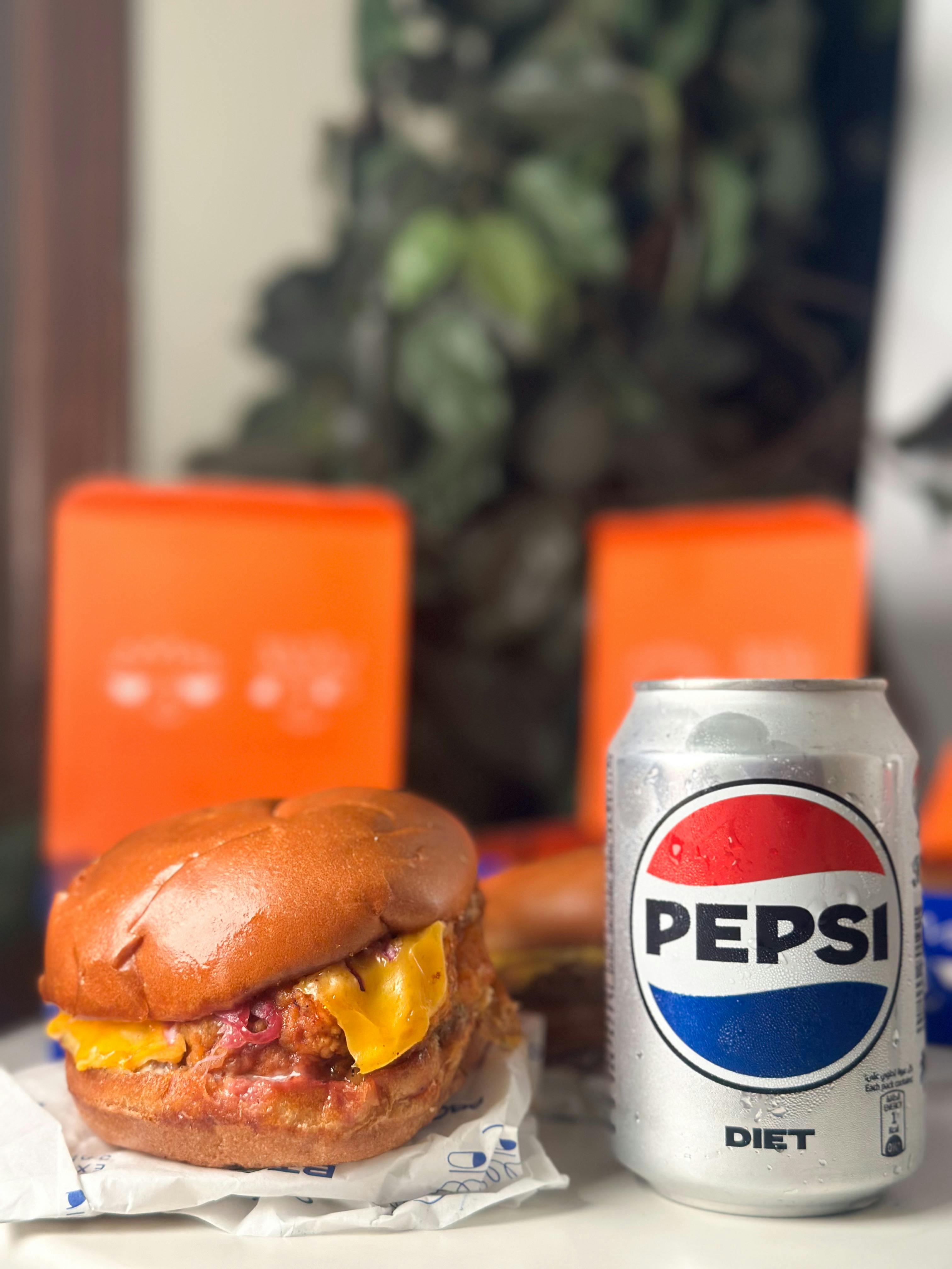 A pepsi and a cheeseburger next to a can of pepsi · Free Stock Photo