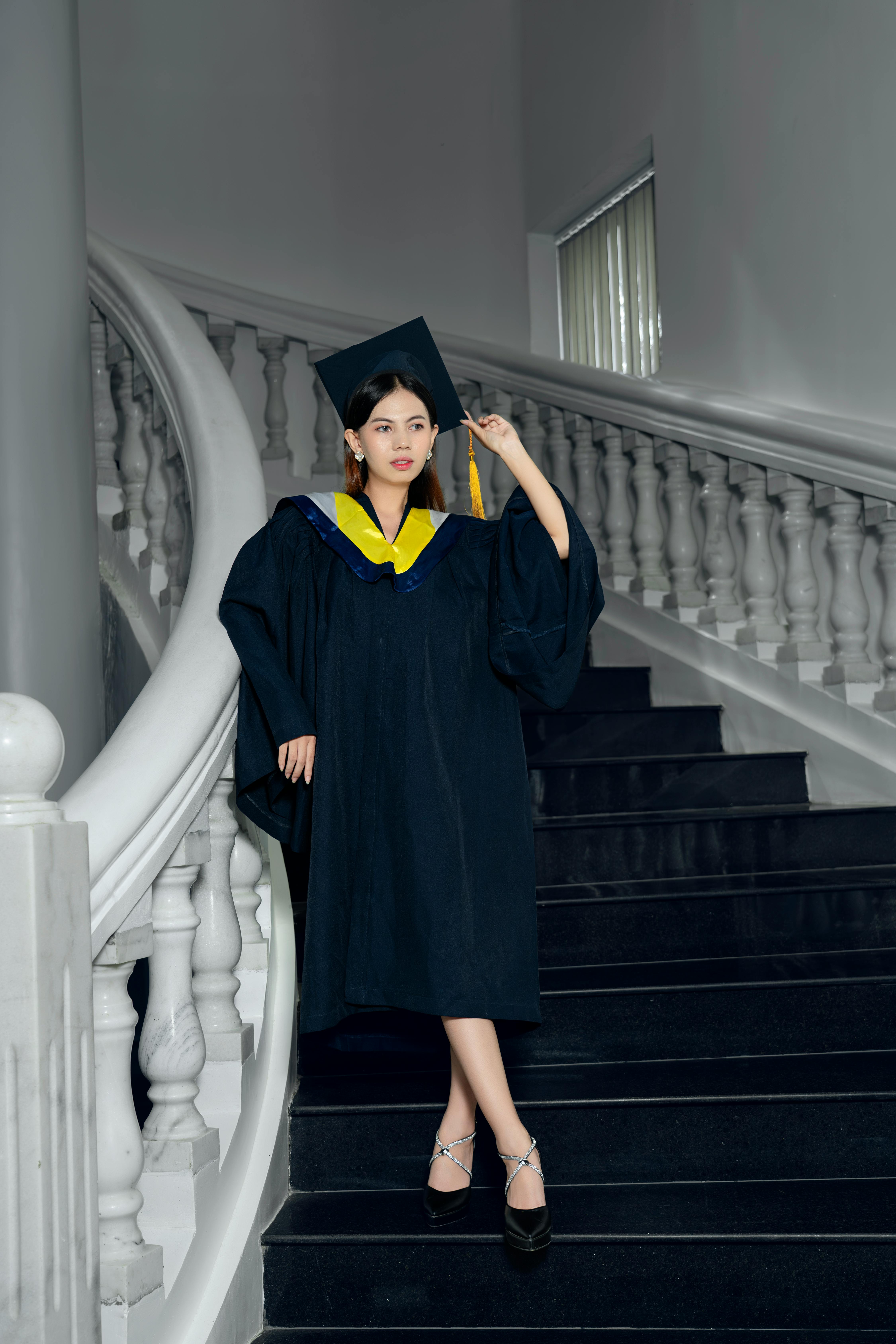 A woman in a graduation gown posing on stairs · Free Stock Photo