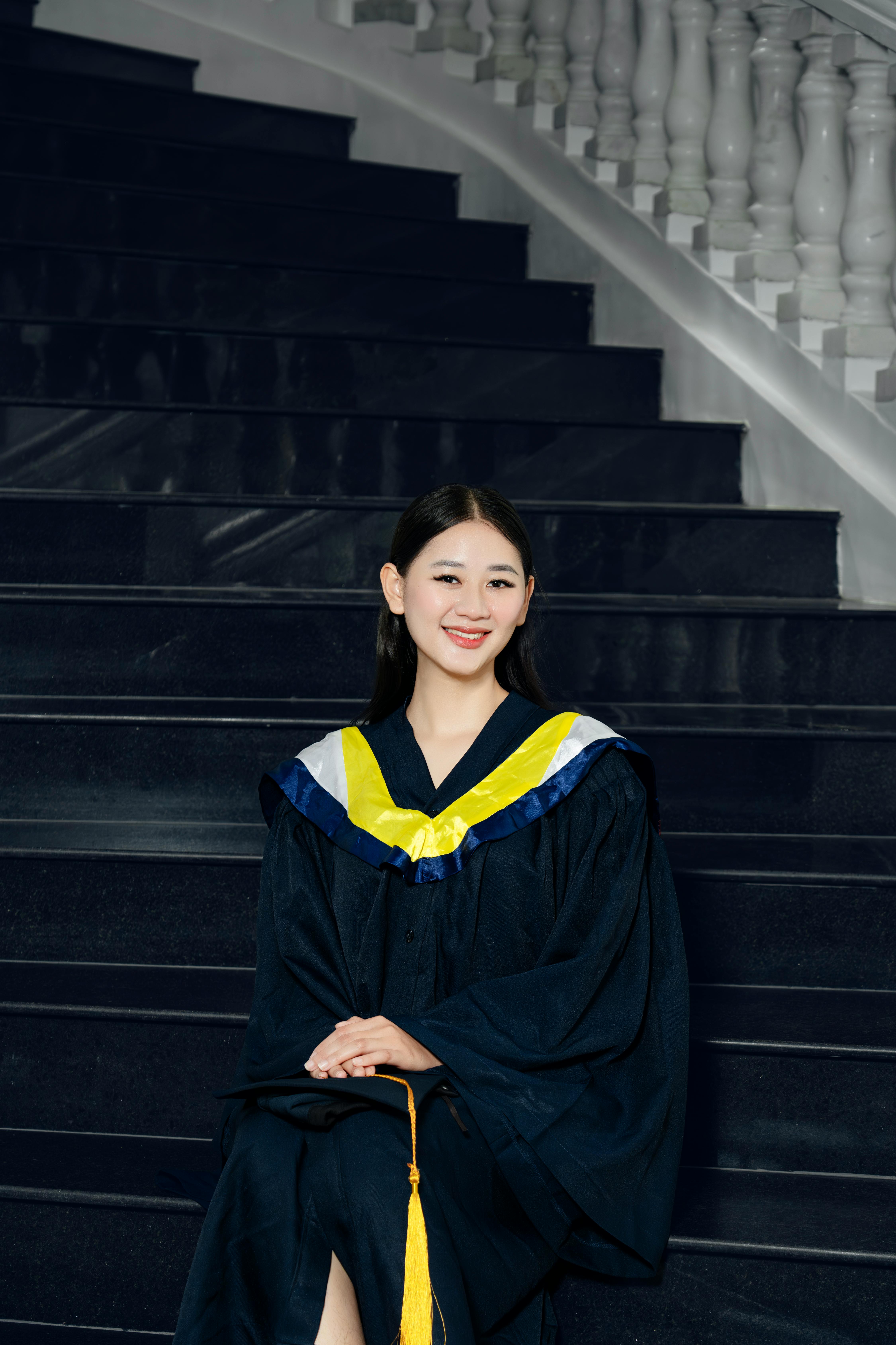A woman in a graduation gown sitting on stairs · Free Stock Photo