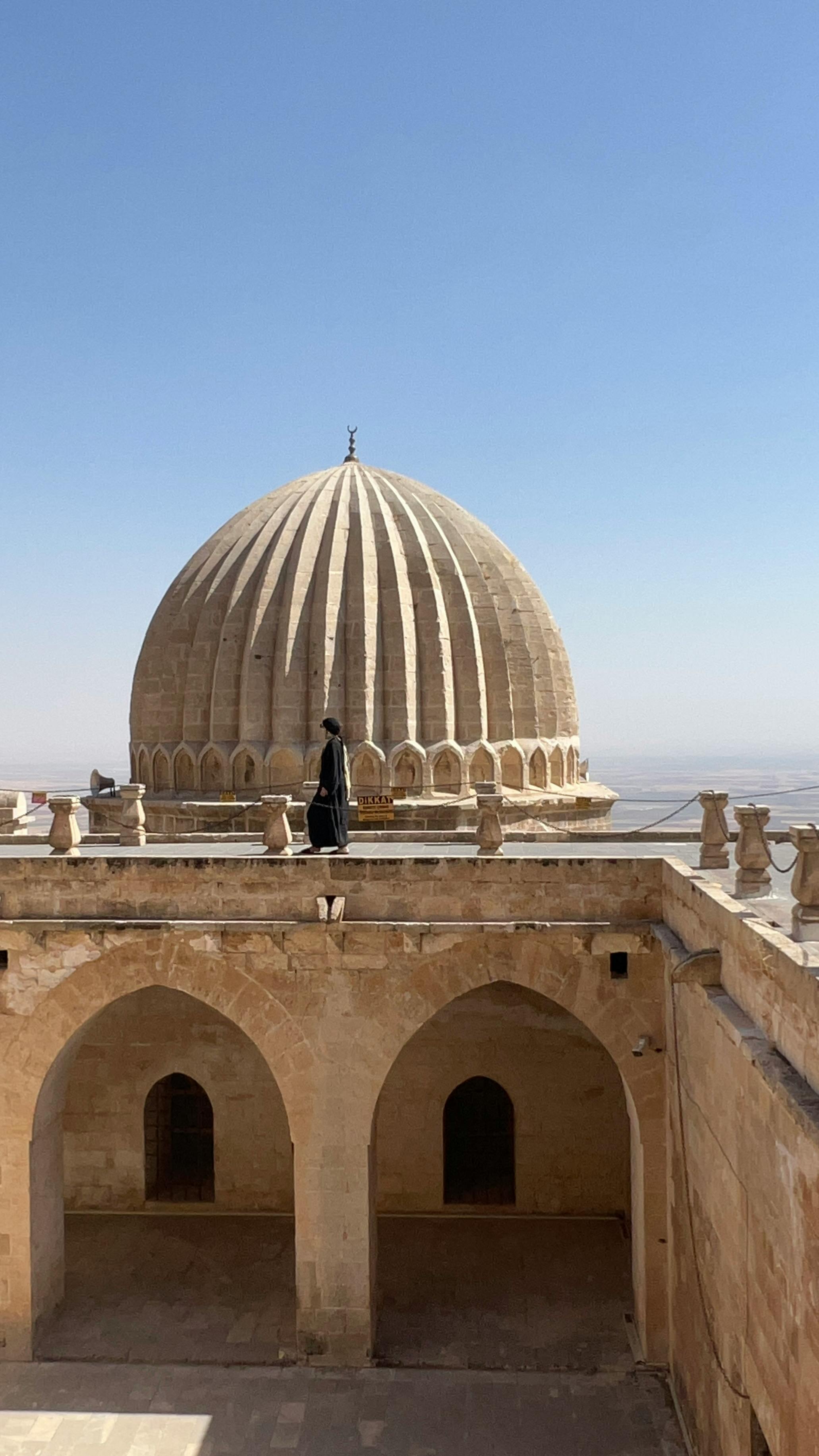 A man stands on top of a dome in a desert · Free Stock Photo