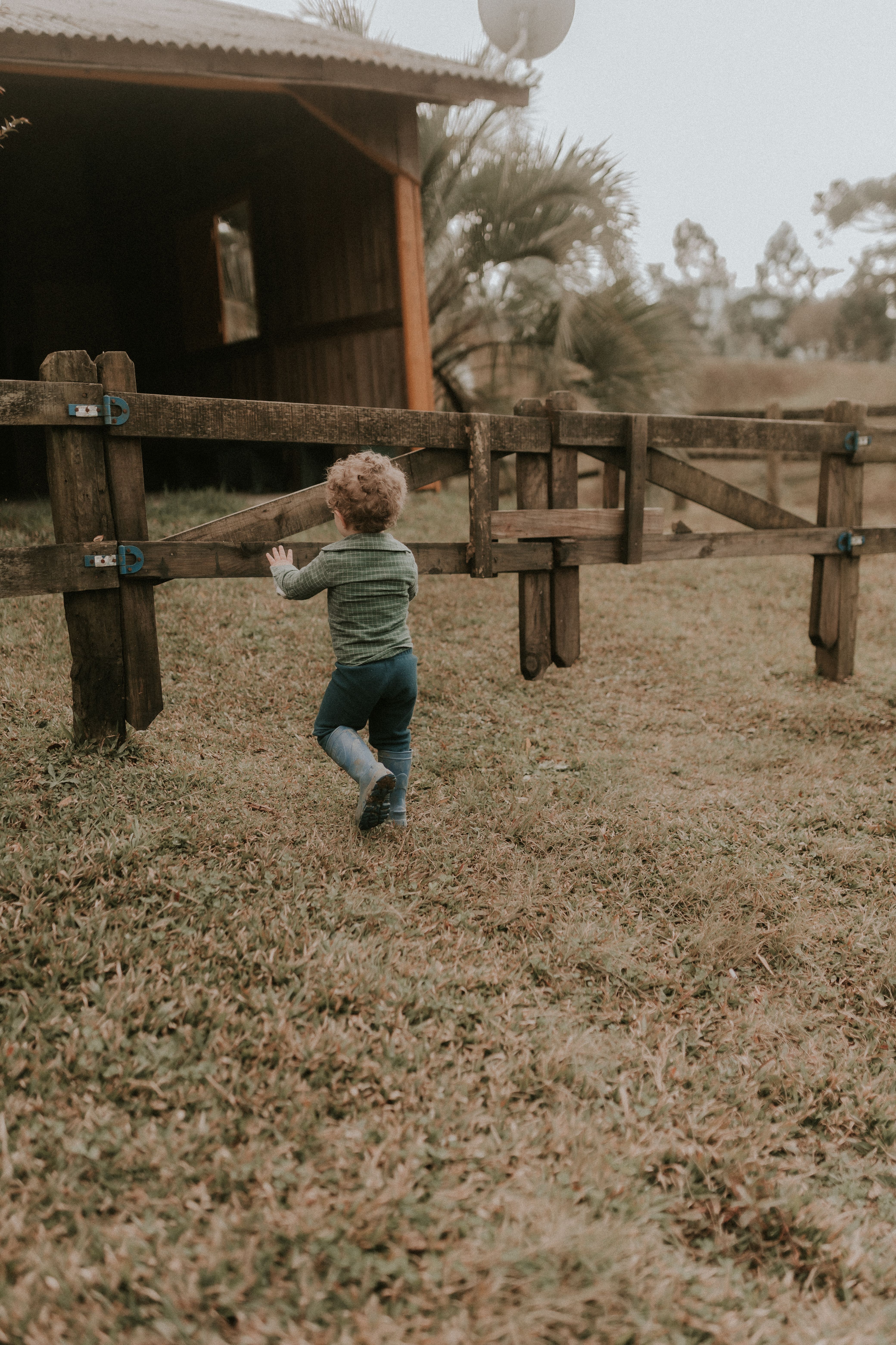 A little boy running through a field with a fence · Free Stock Photo