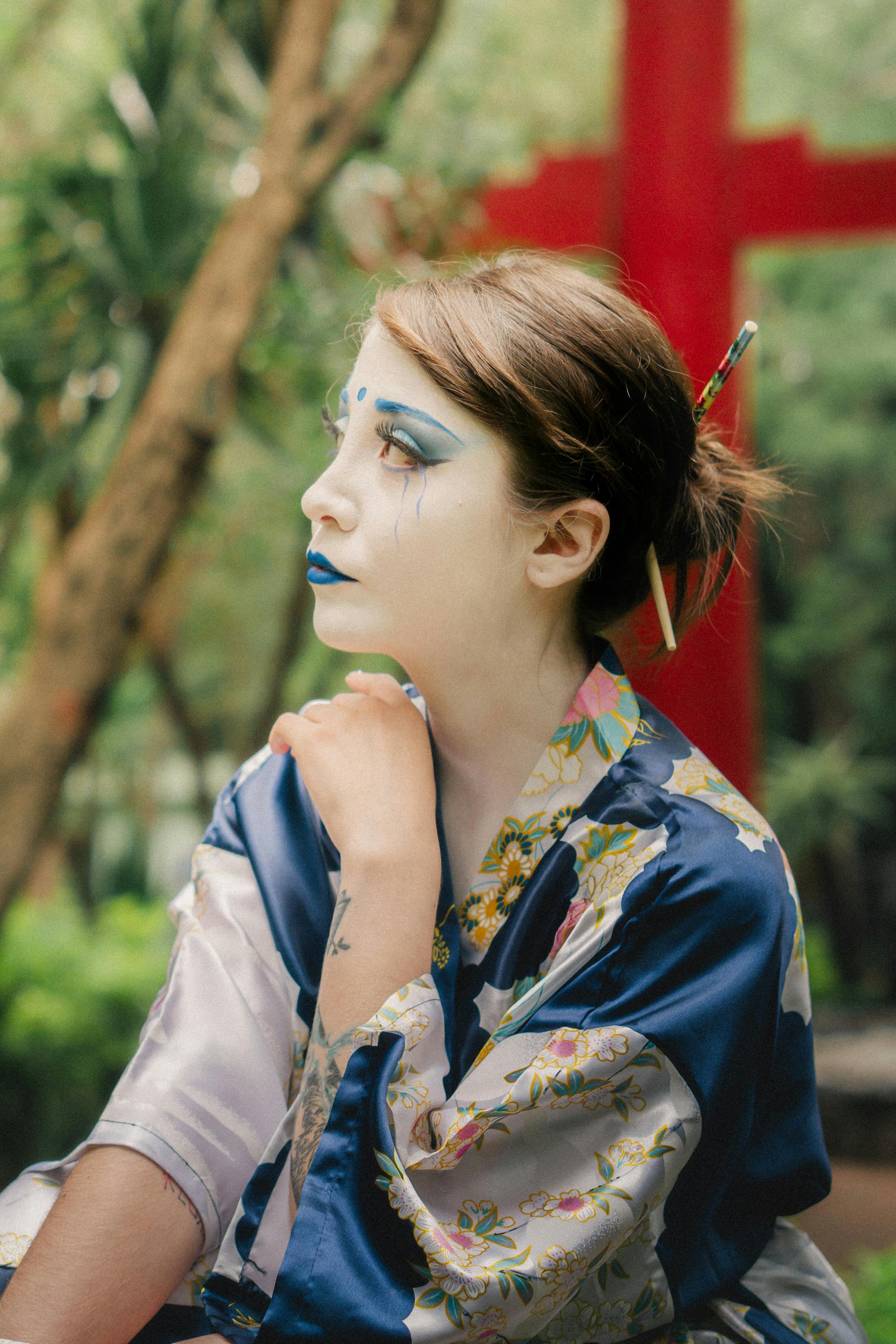 A woman in a geisha costume sitting on the ground · Free Stock Photo