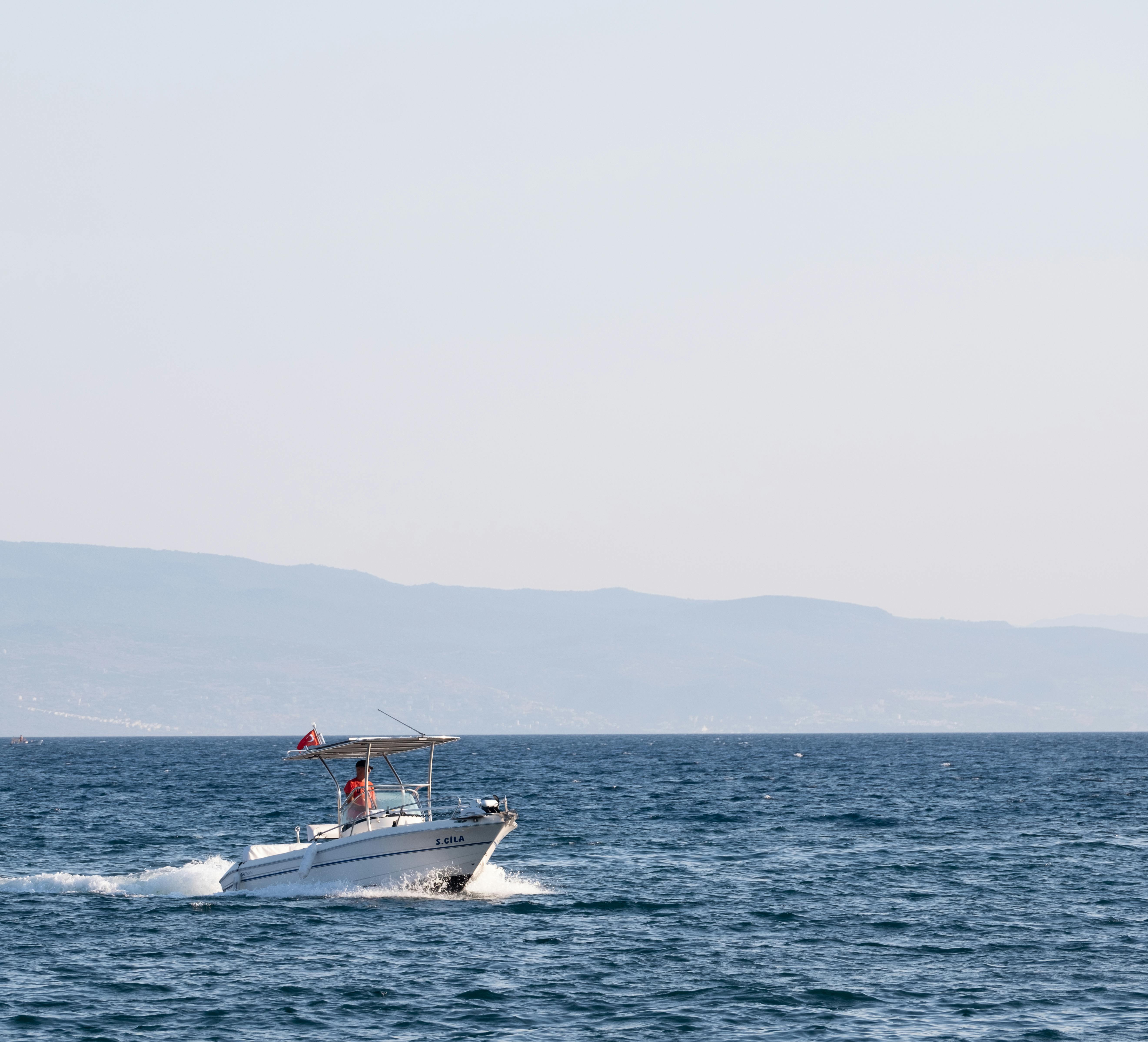 A boat is traveling on the water with mountains in the background ...
