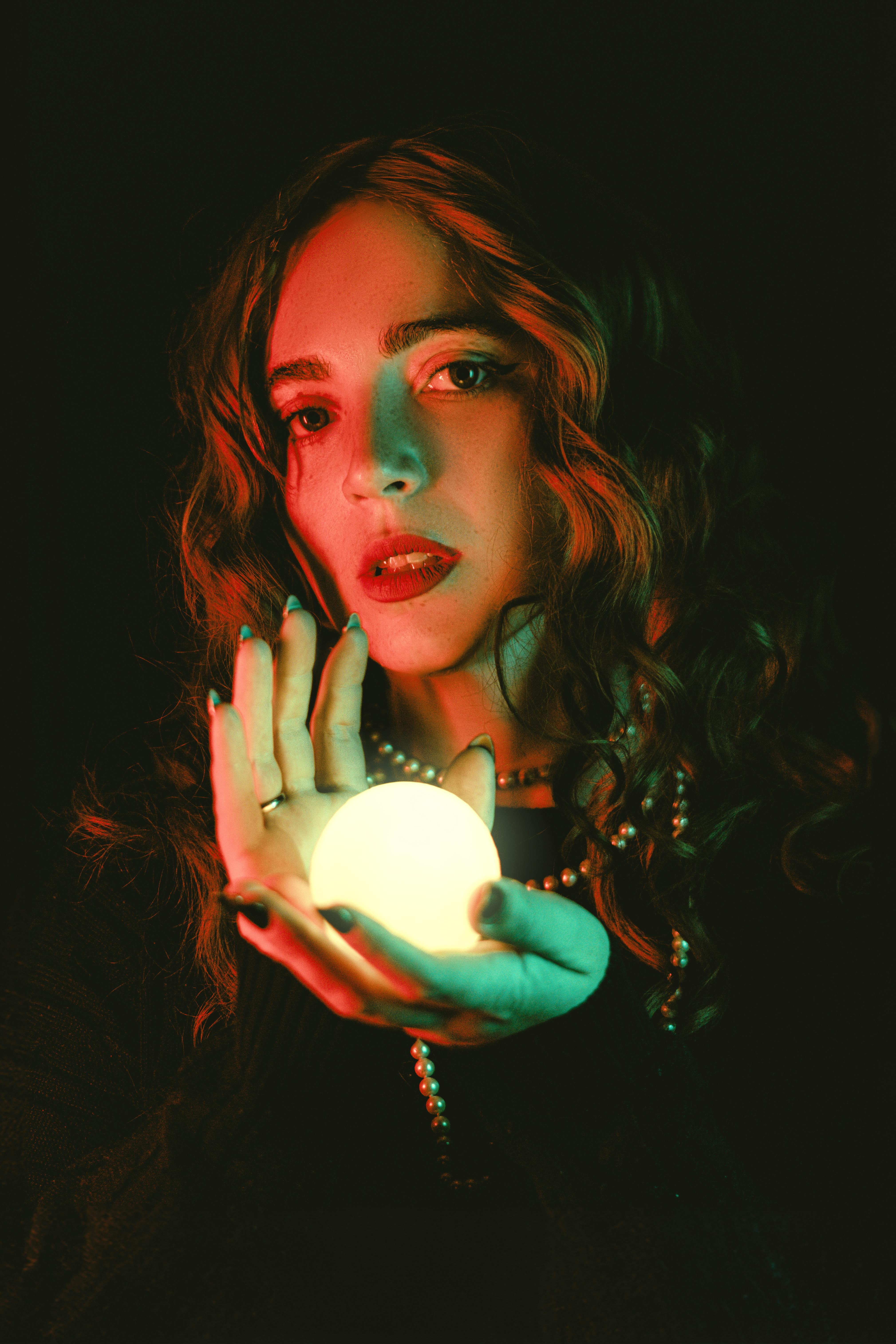 A woman holding a glowing orb in her hand · Free Stock Photo